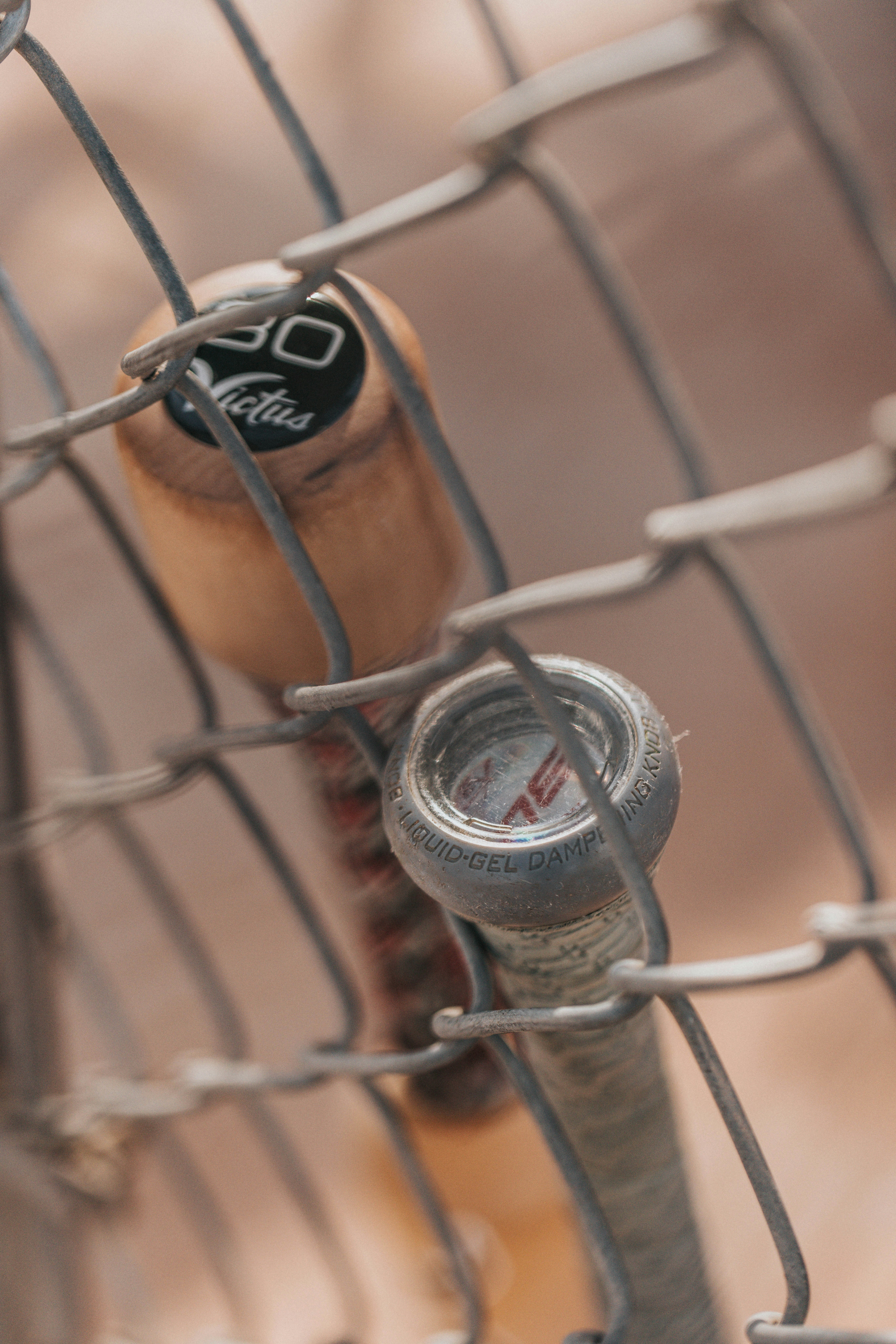 Baseball bats are stuck behind a chain-link fence. photo – Free ...