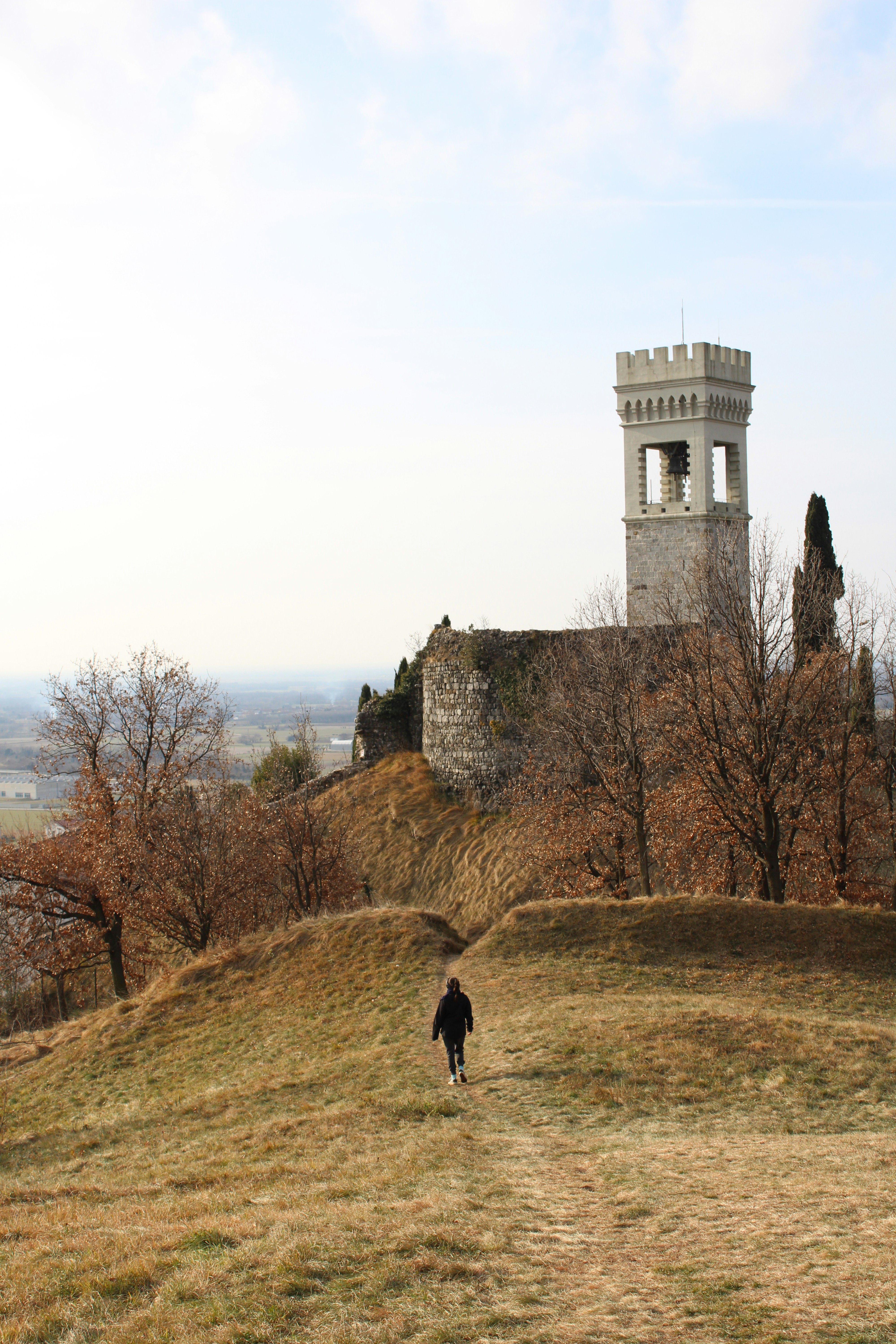 Hilltop Sentinel: A lone traveler approaches a medieval tower on a wind-swept hill