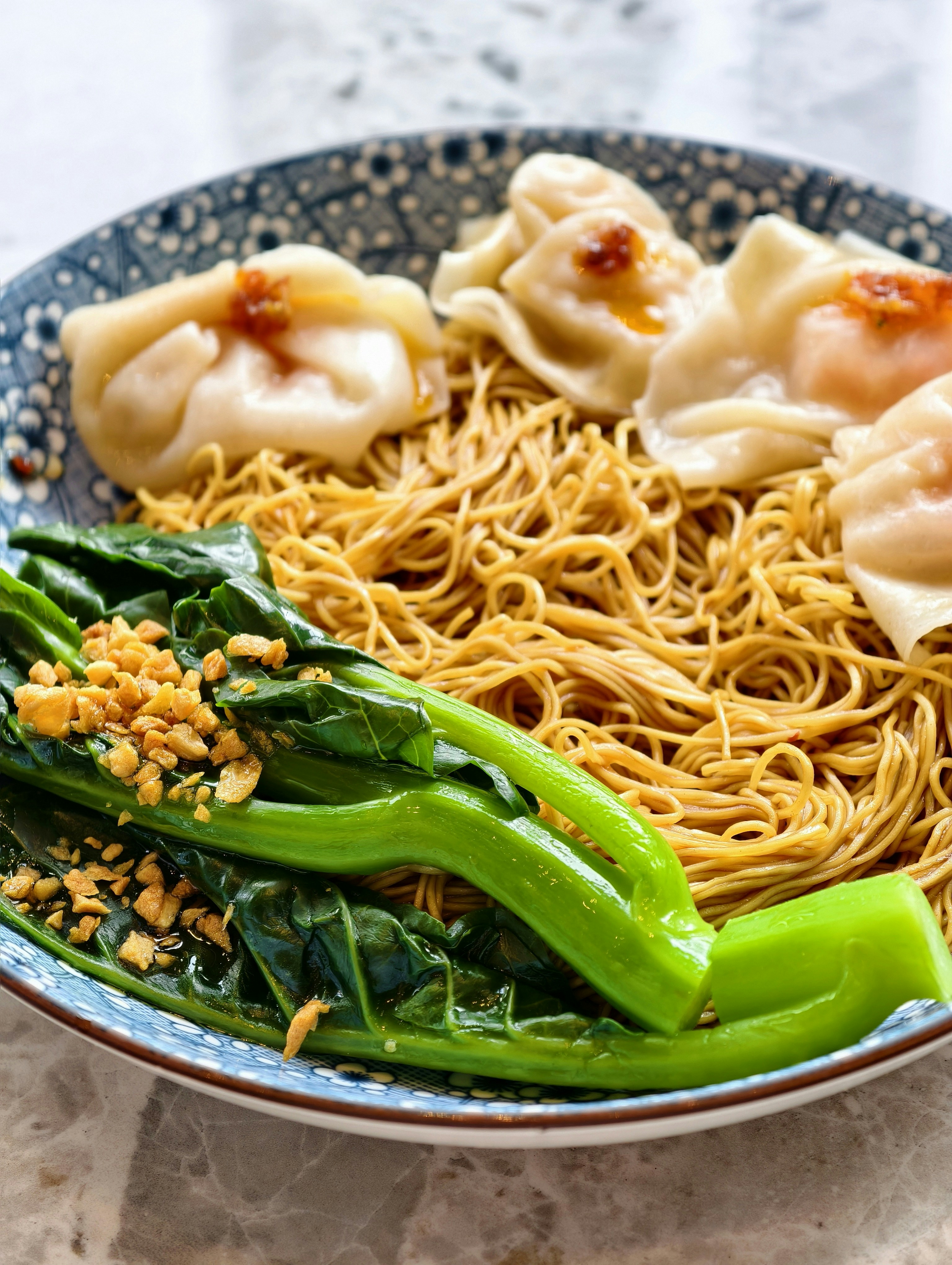 Delicious plate featuring noodles, dumplings, and vibrant greens topped with crushed peanuts.
