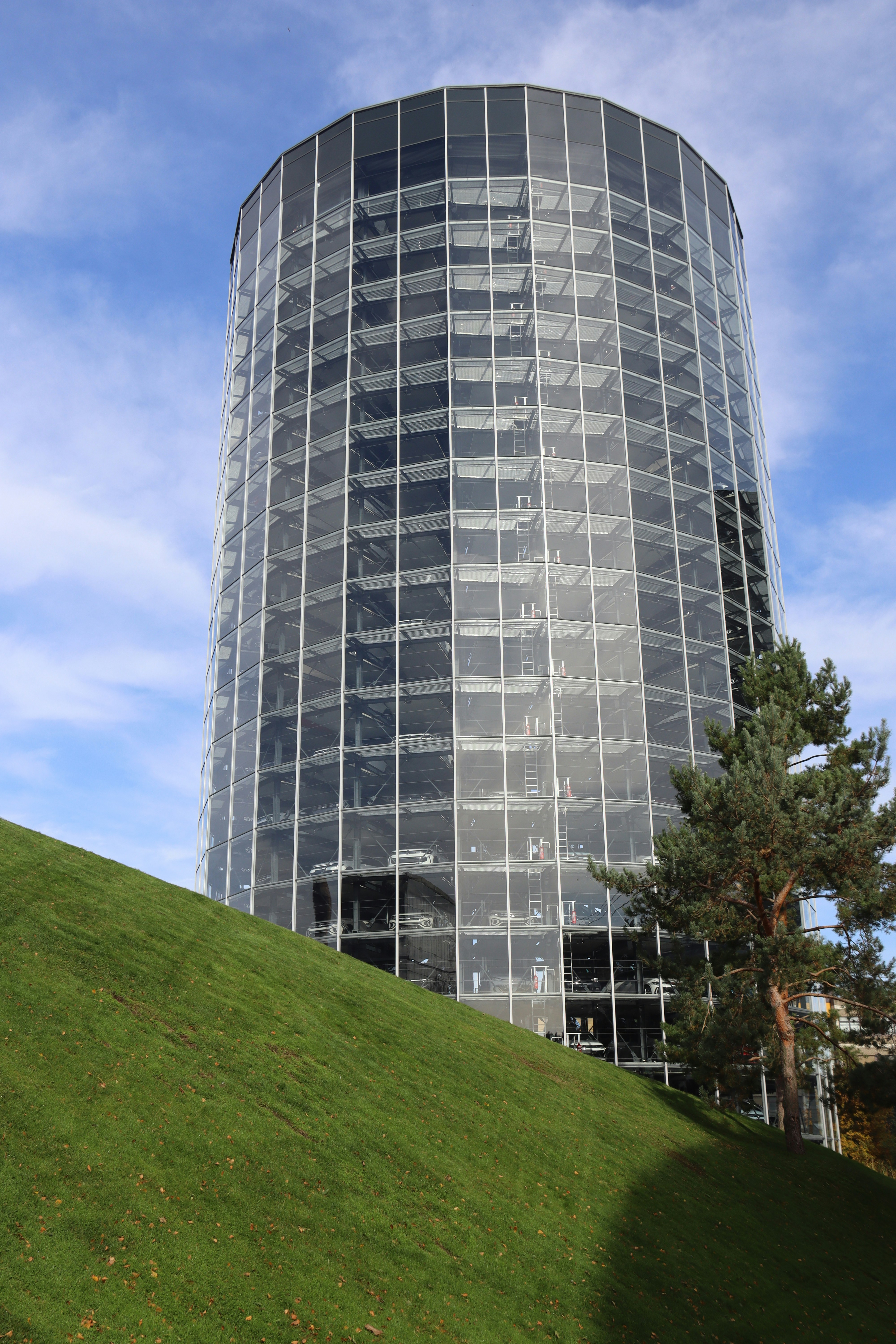Cylindrical Glass Tower Framed by a Sloping Green Hill