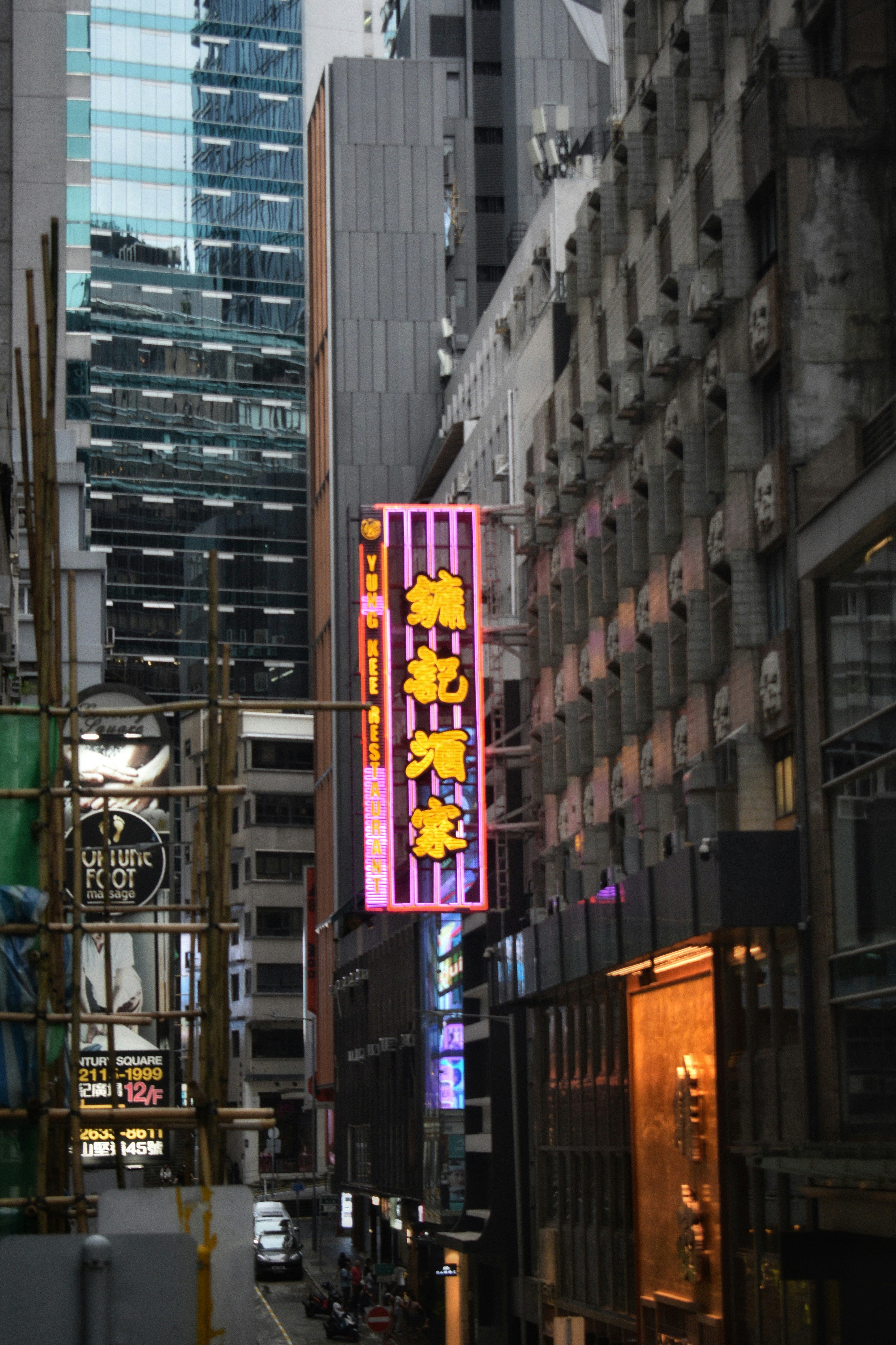 Vertical Neon Glyphs Framing a Dusk Street Canyon