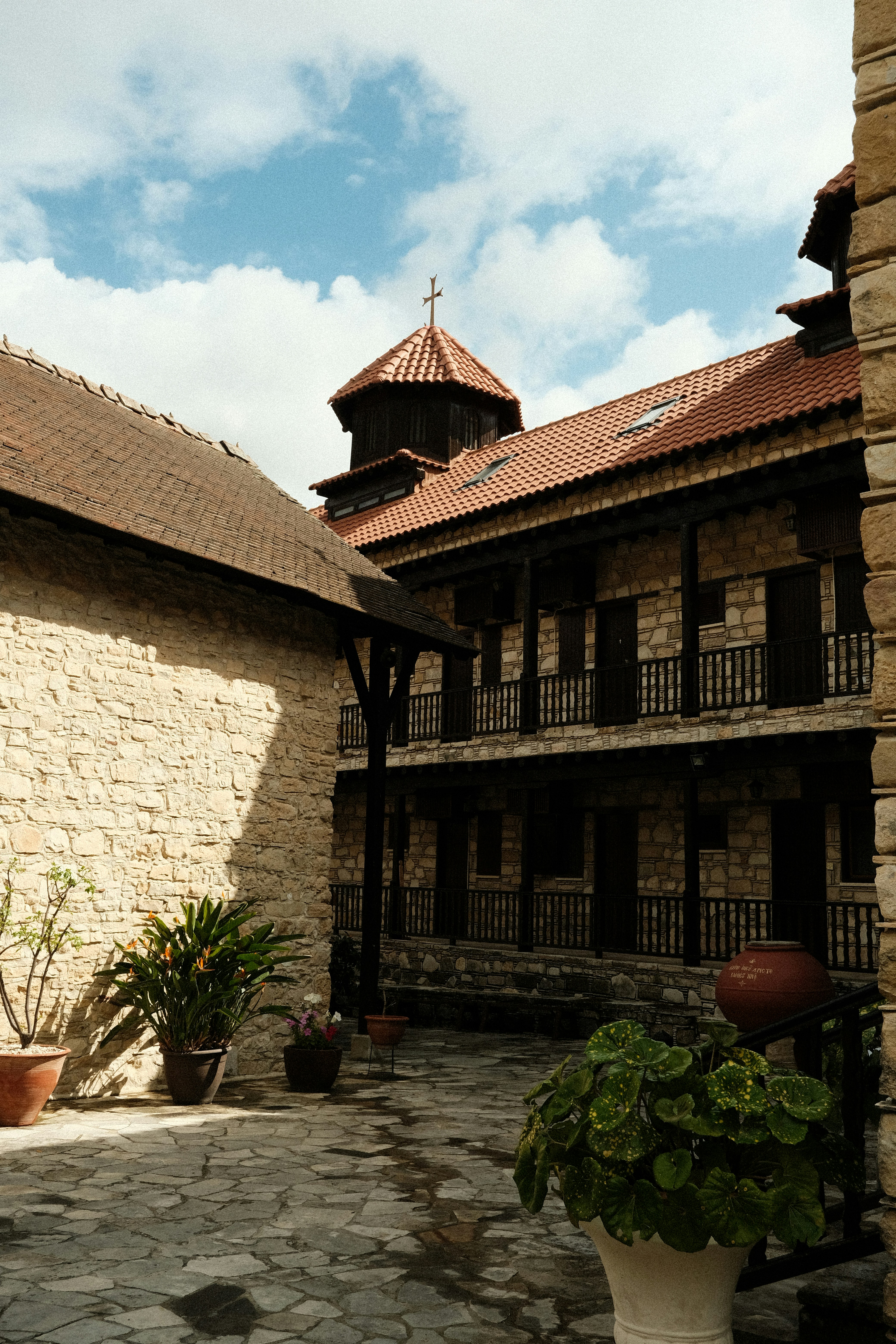 Cross-Topped Tower Rising Over a Sunlit Stone Cloister