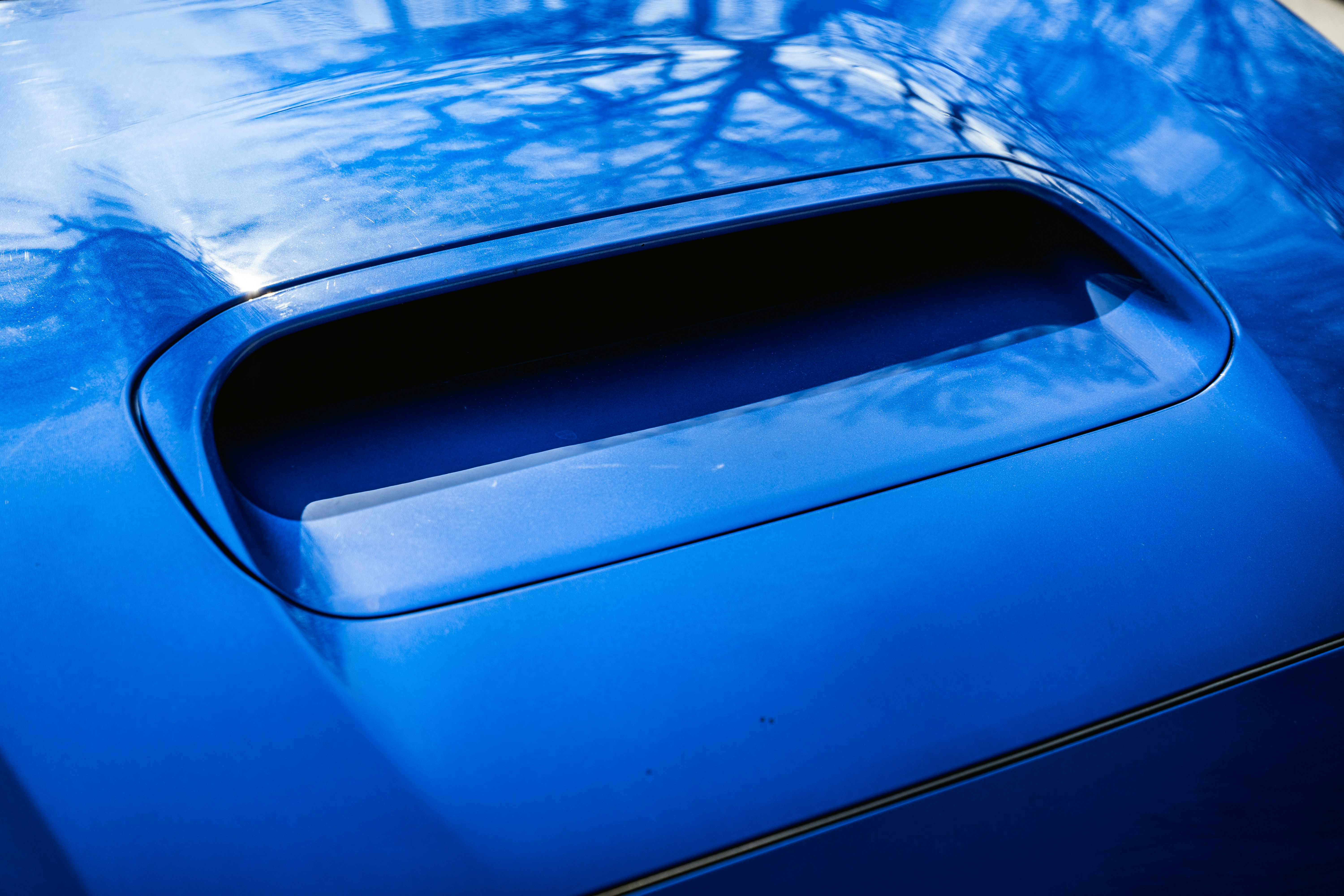 Here is a possible caption: **blue car hood with an air scoop.** photo ...