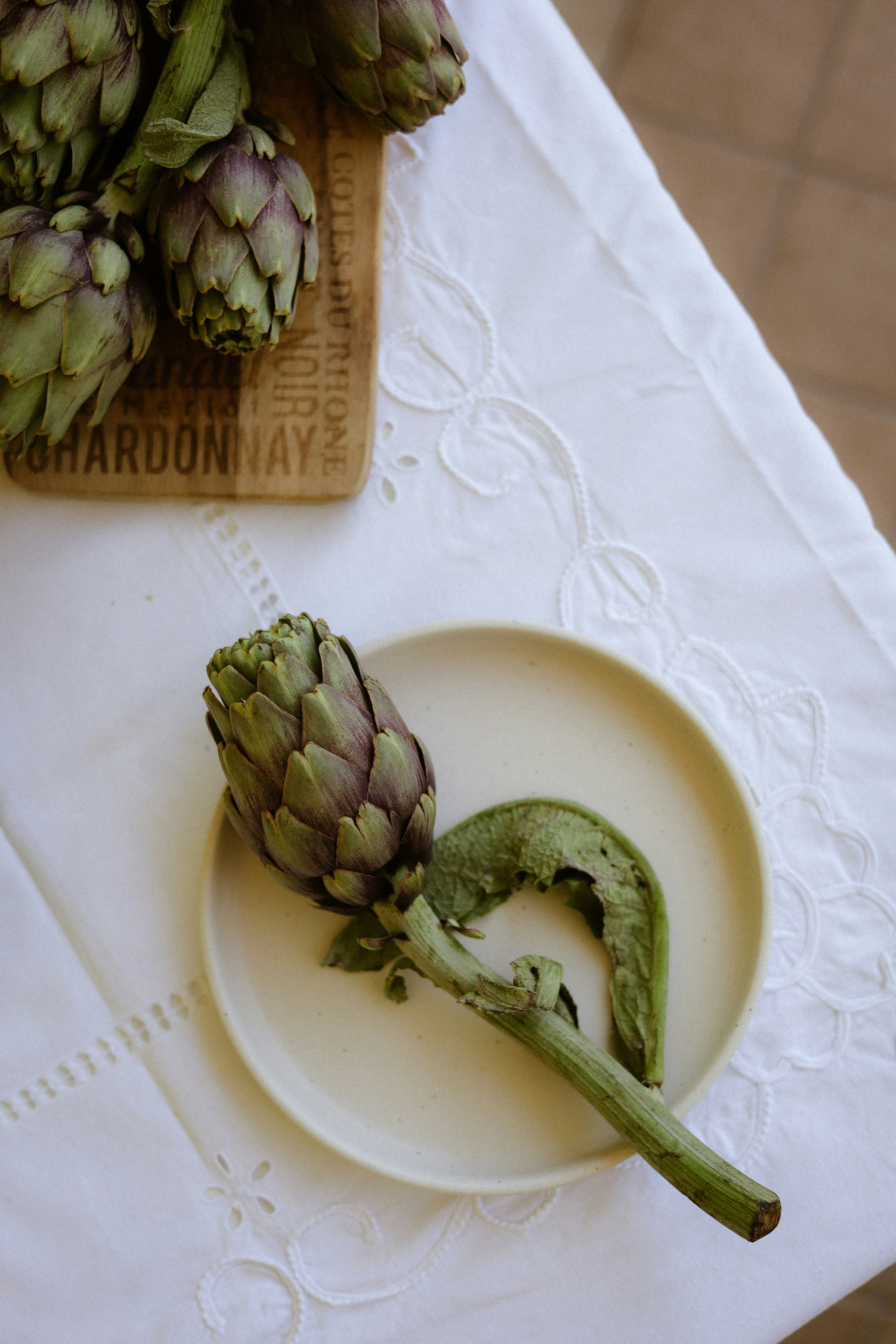Artichoke on embroidered linen: a quiet study of texture and light
