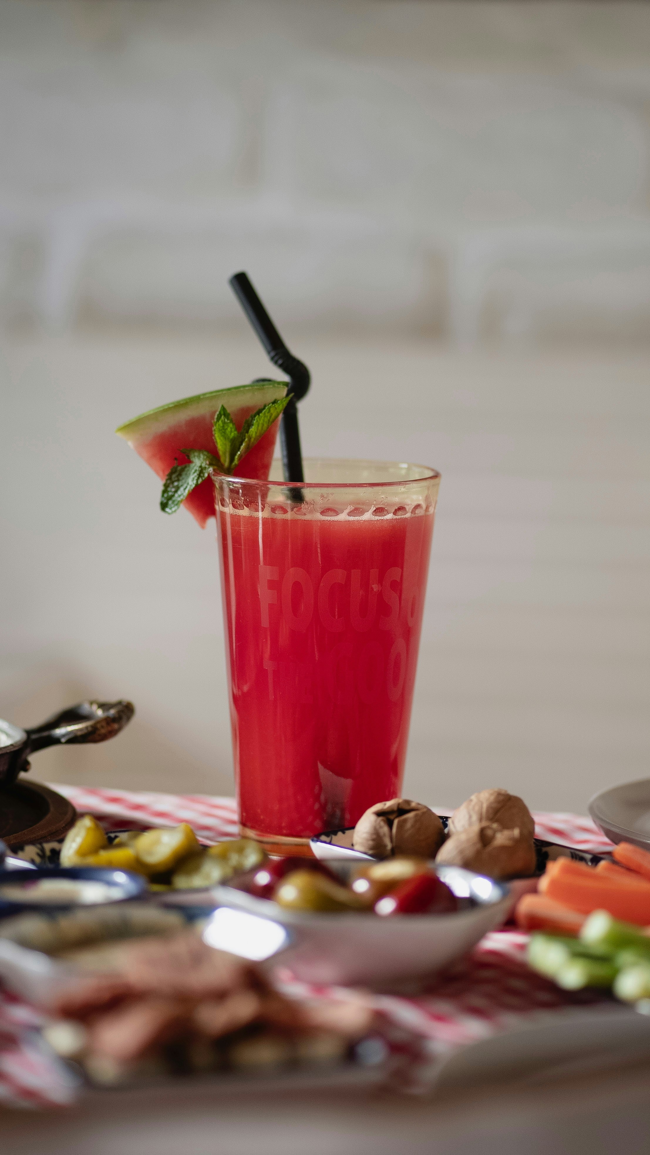 Juice in Focus: A Glass of Pink Refreshment at a Table laden with Treats