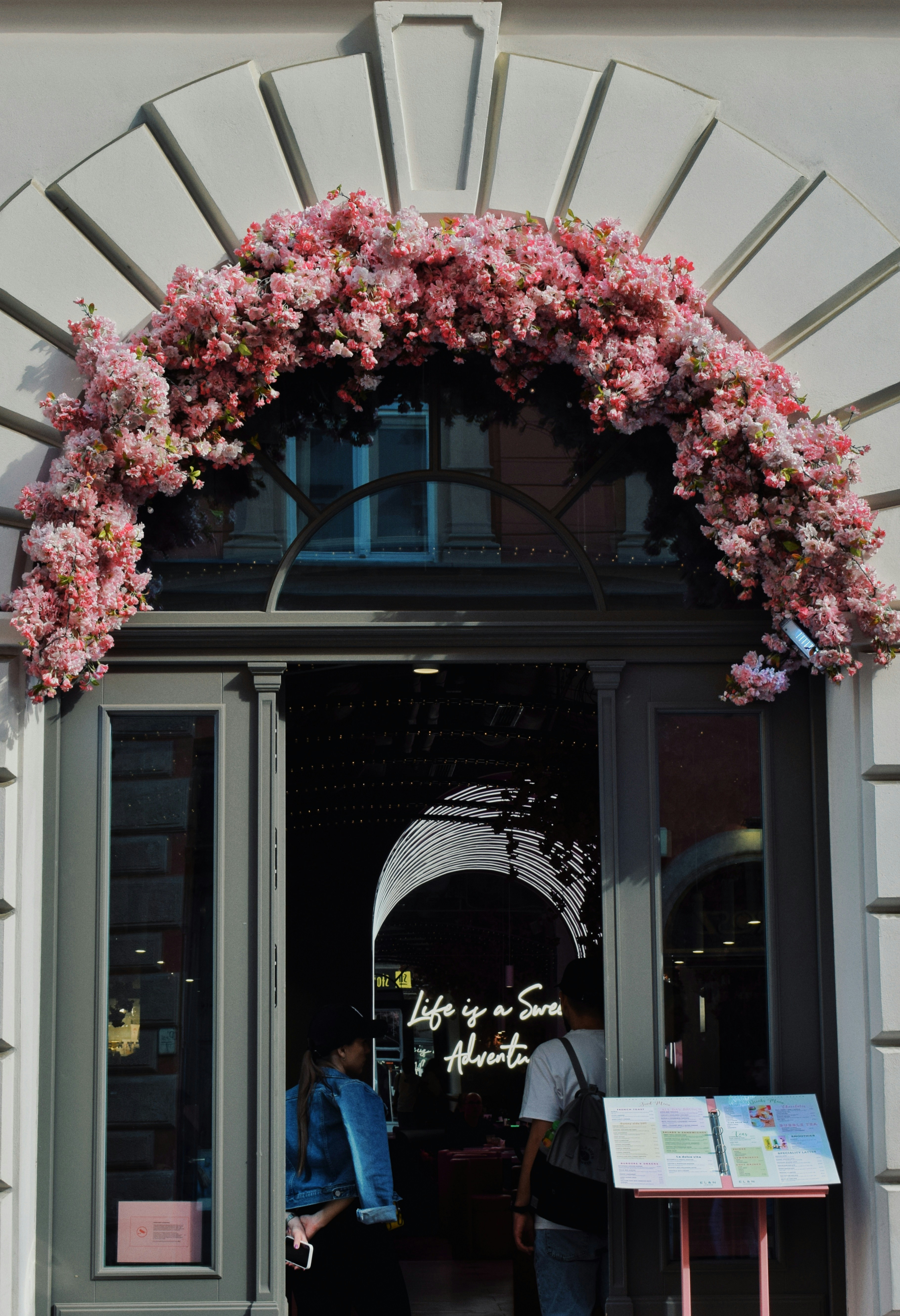 Floral Archway Framing a City Entrance with Neon Sign