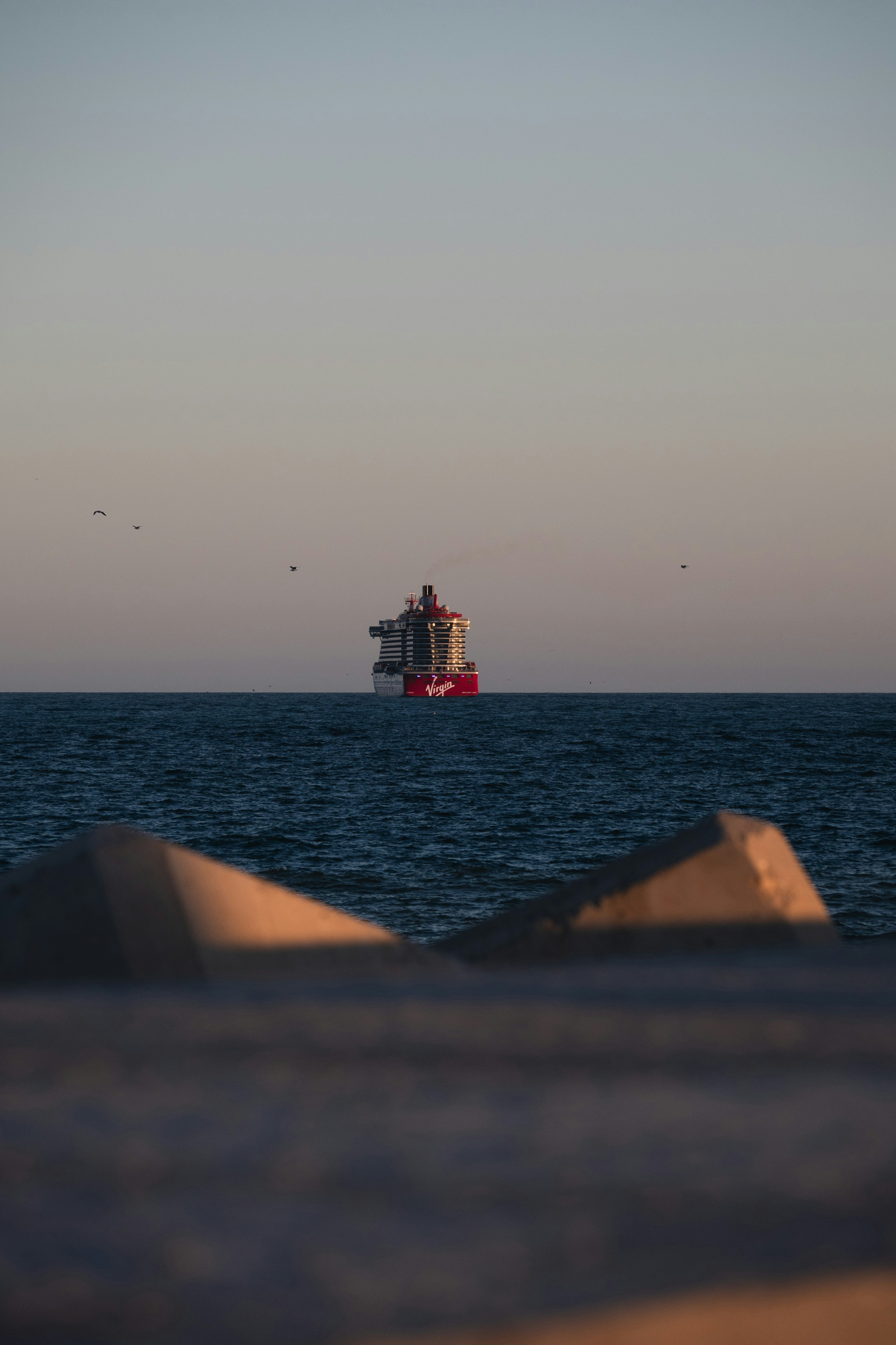 Red-hulled behemoth at sea: a lone cargo ship on the horizon