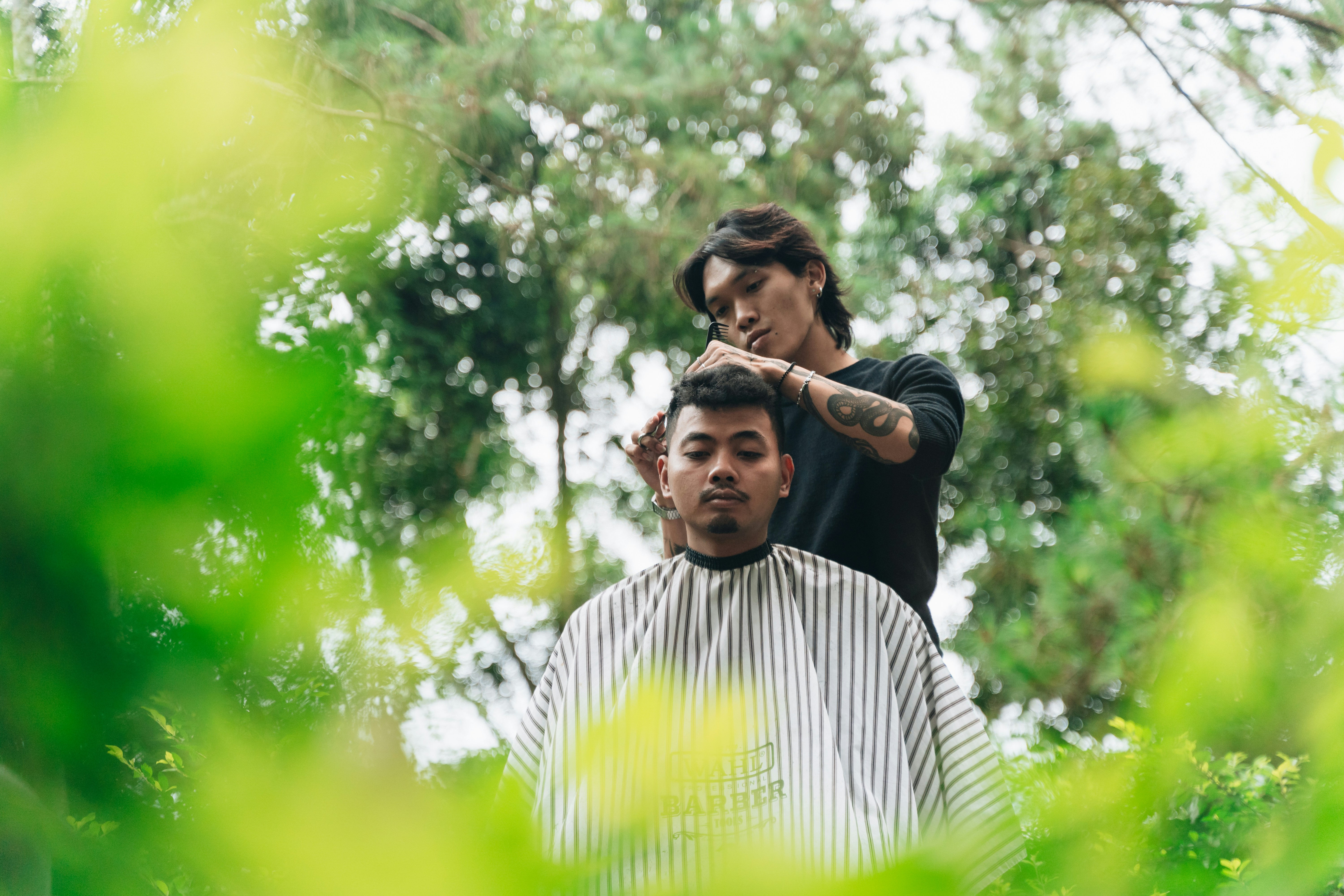 Barber gives a haircut outdoors under the trees. photo – Free Image on ...
