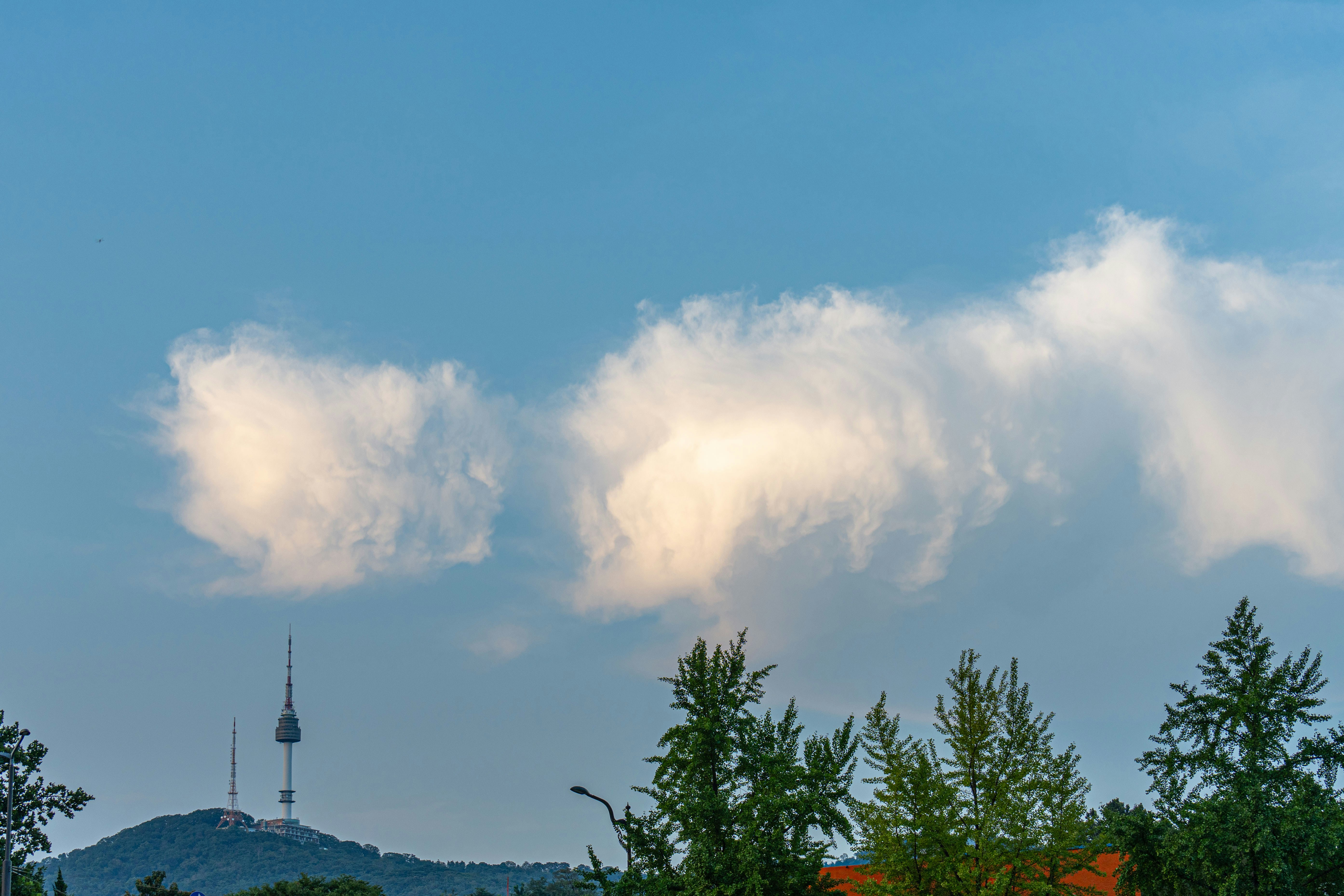 Distant Tower on a Green Hill Beneath Whispering Clouds