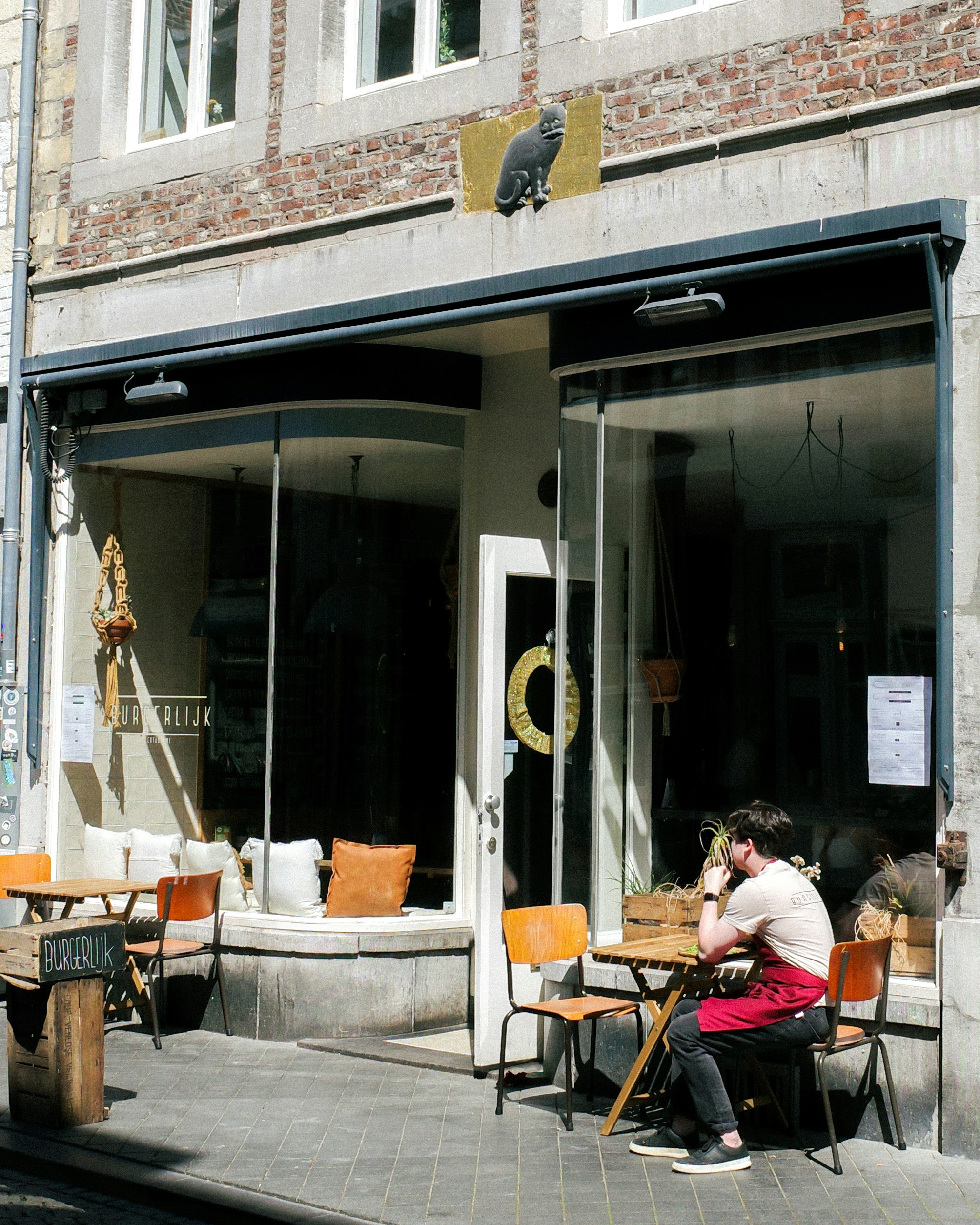 A man sits outside a shop. photo – Free Cafe Image on Unsplash