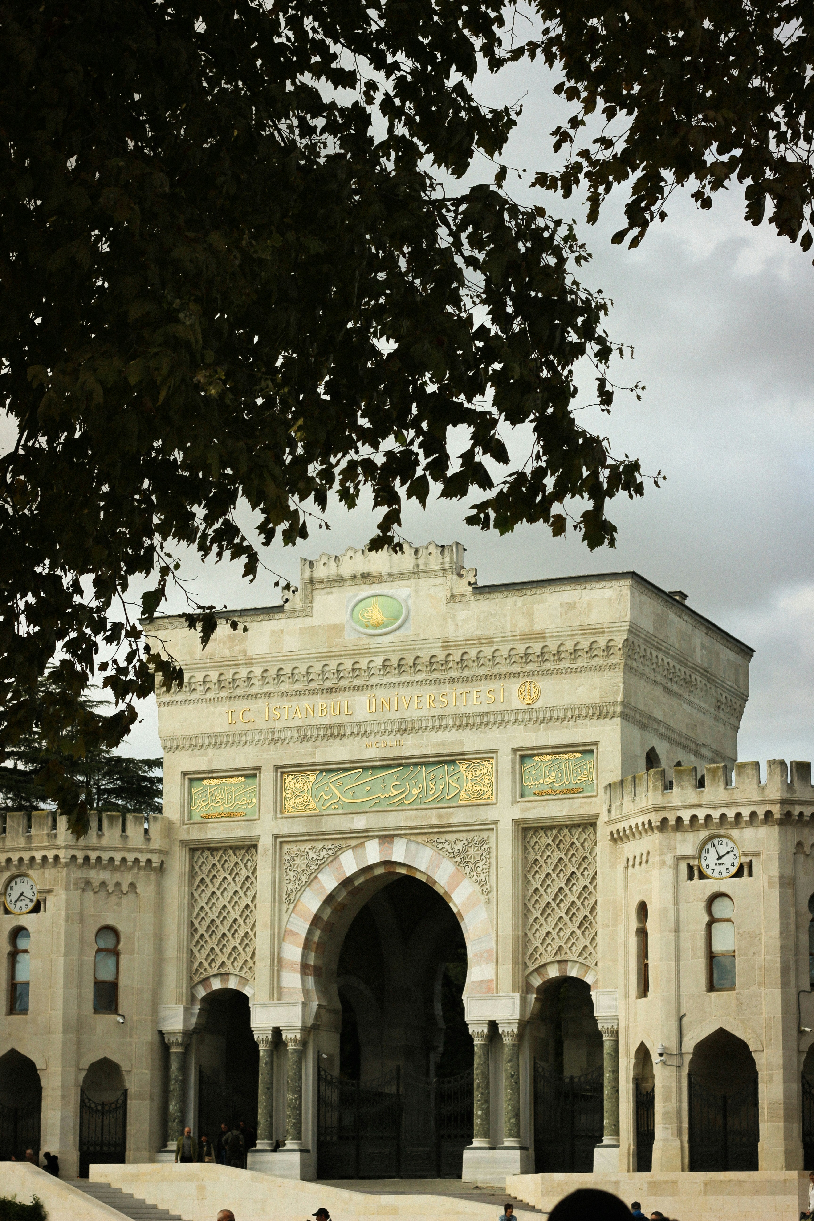 Leaf-Framed Arch Gate of Istanbul University: Stone Portal Beneath a Shaded Canopy