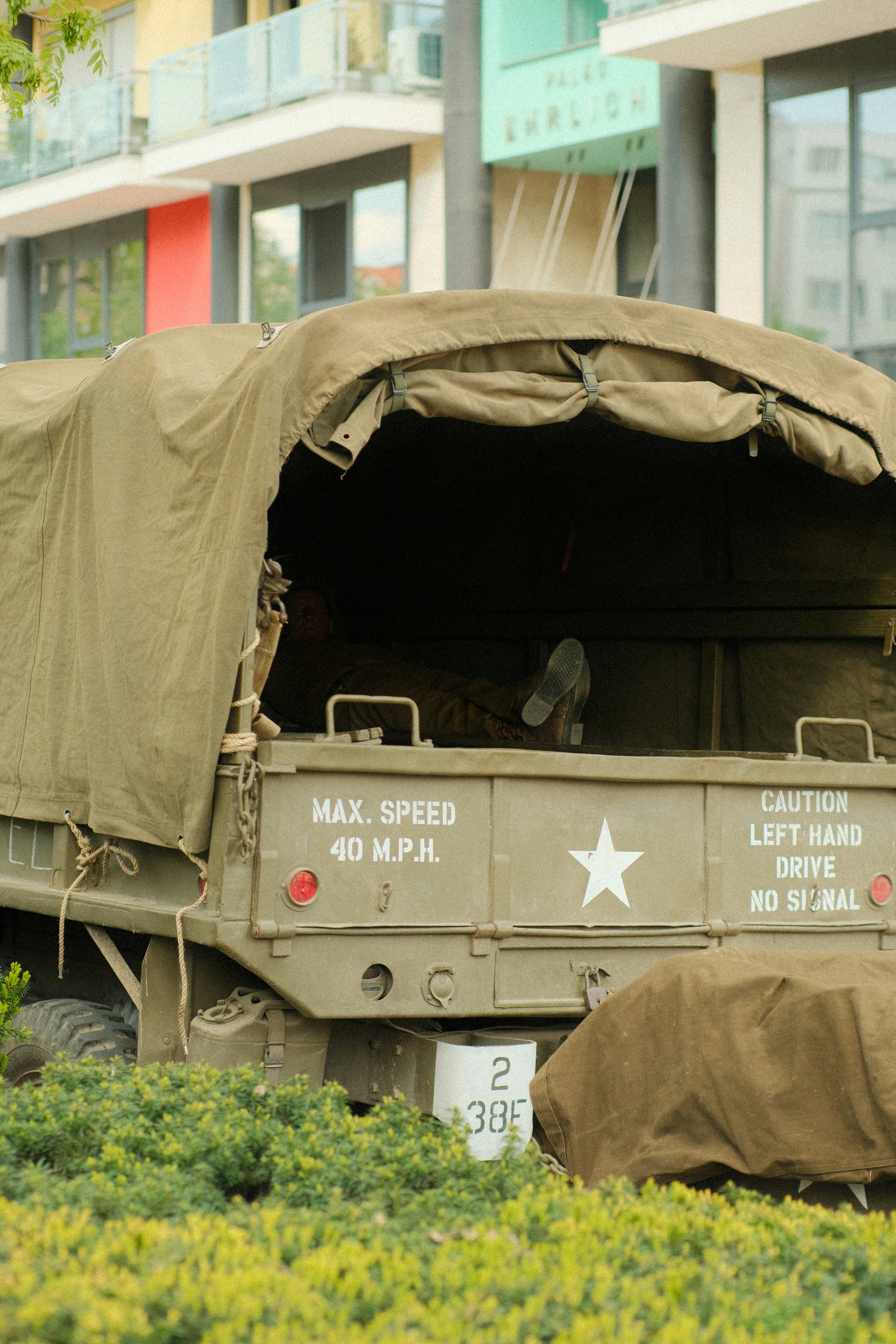 Camo by the Shopfronts: A WWII-era Army Truck in a Quiet City Street