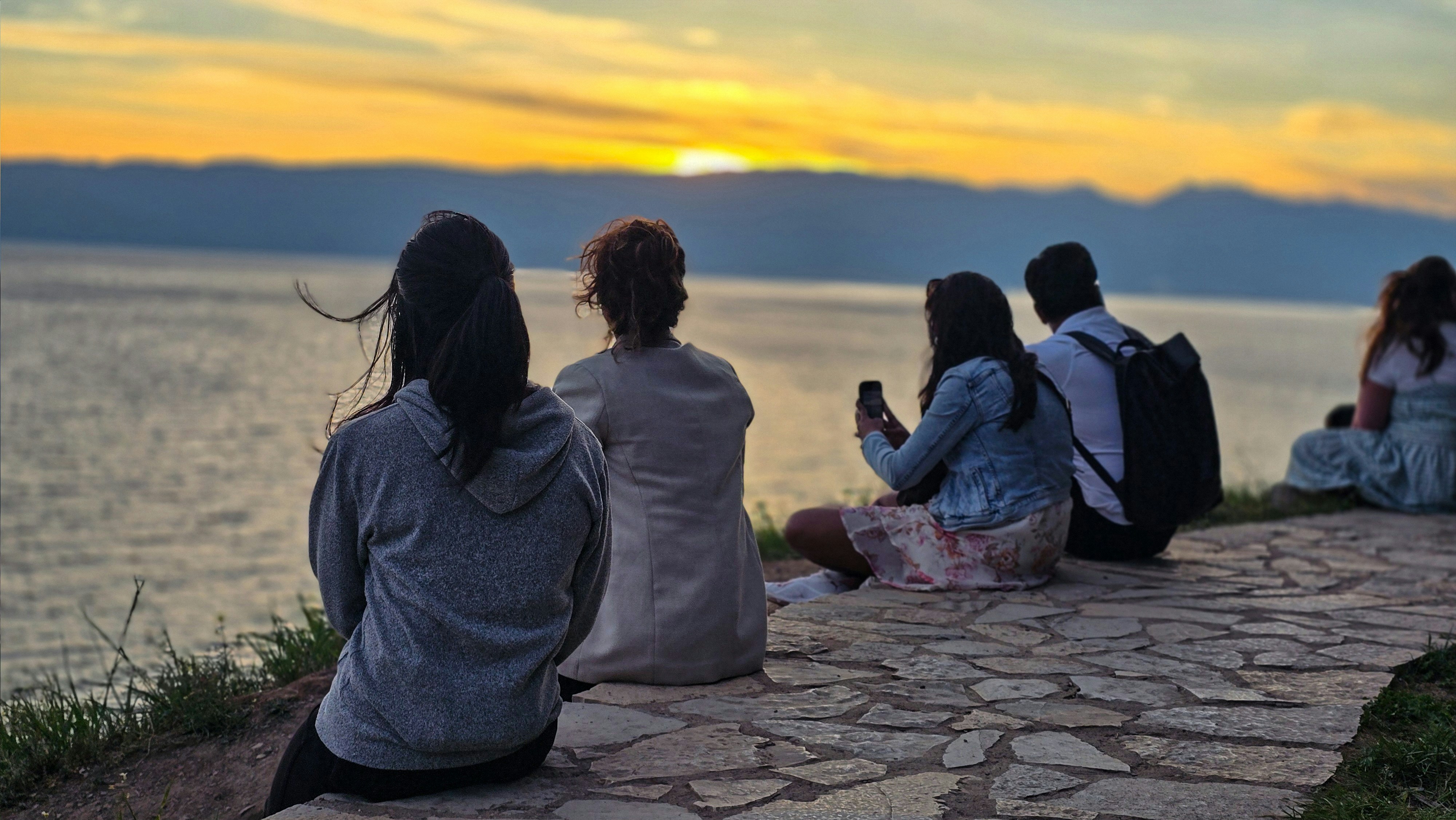Sunset Promenade: Silhouettes Along a Lakefront Ledge
