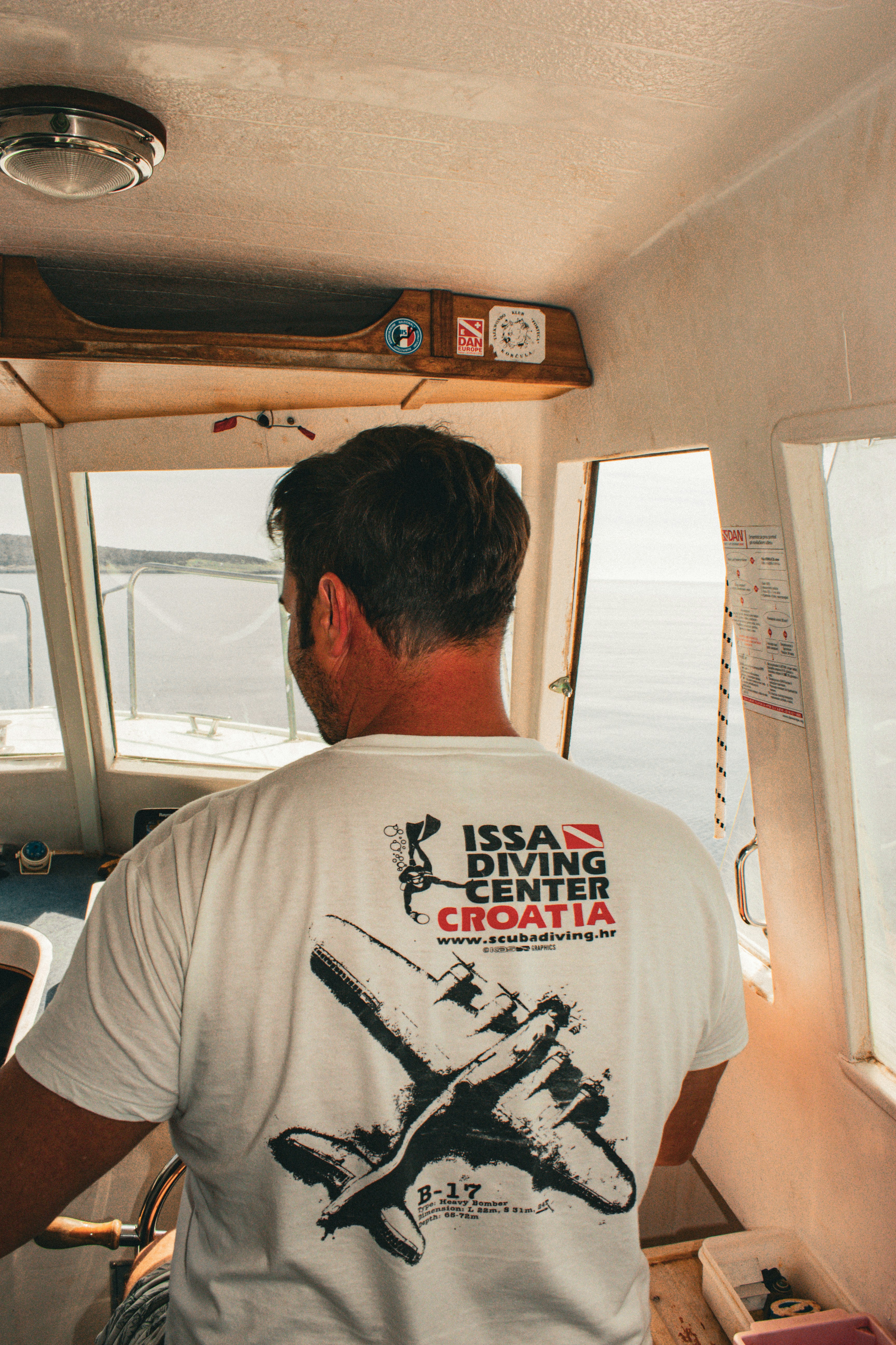 Crewman at the Helm: The White T‑Shirt Scene Inside a Small Diving Vessel