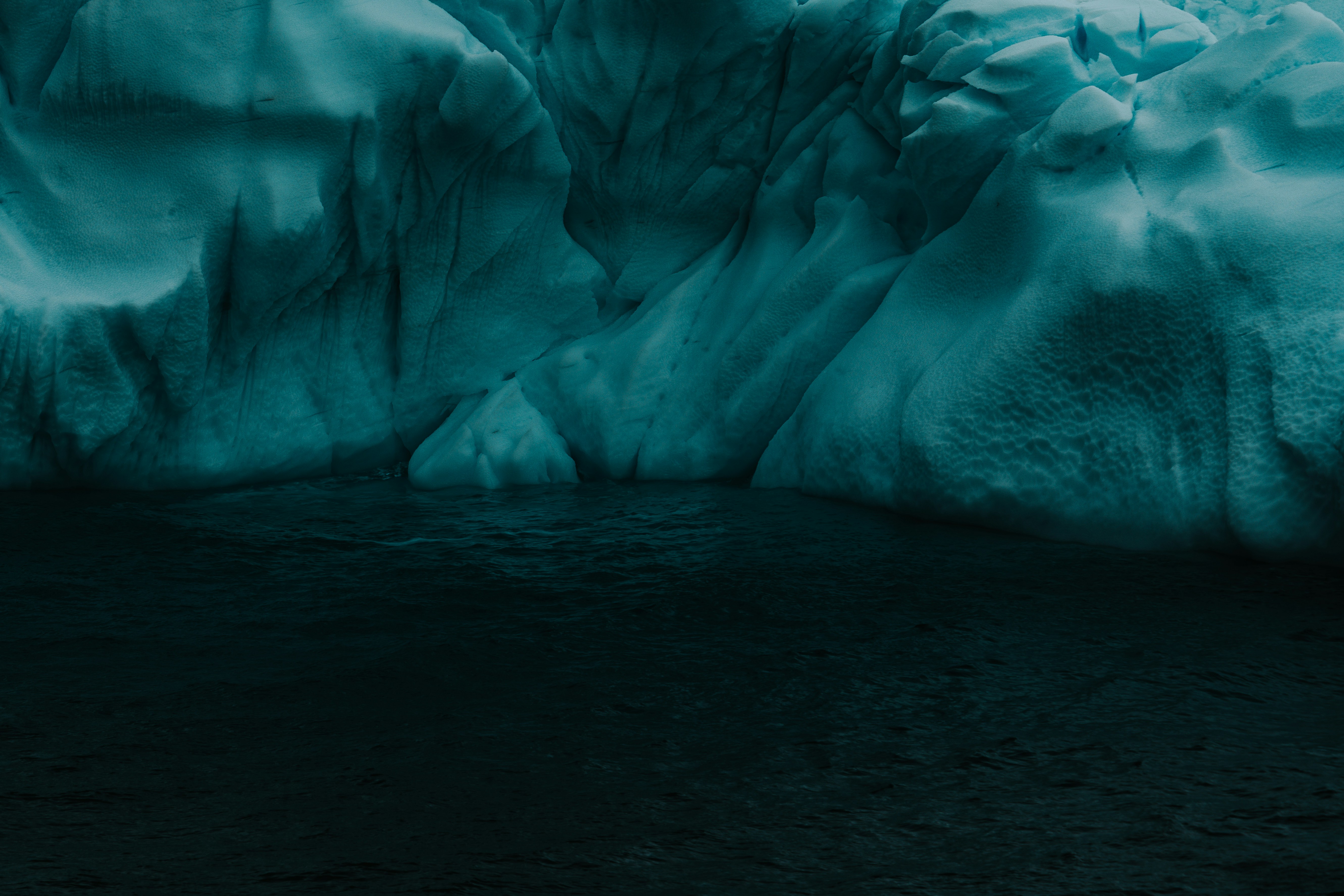 Intricate patterns of glacial ice contrasting with dark water reflections, showcasing the textures and hues of nature's frozen artistry.