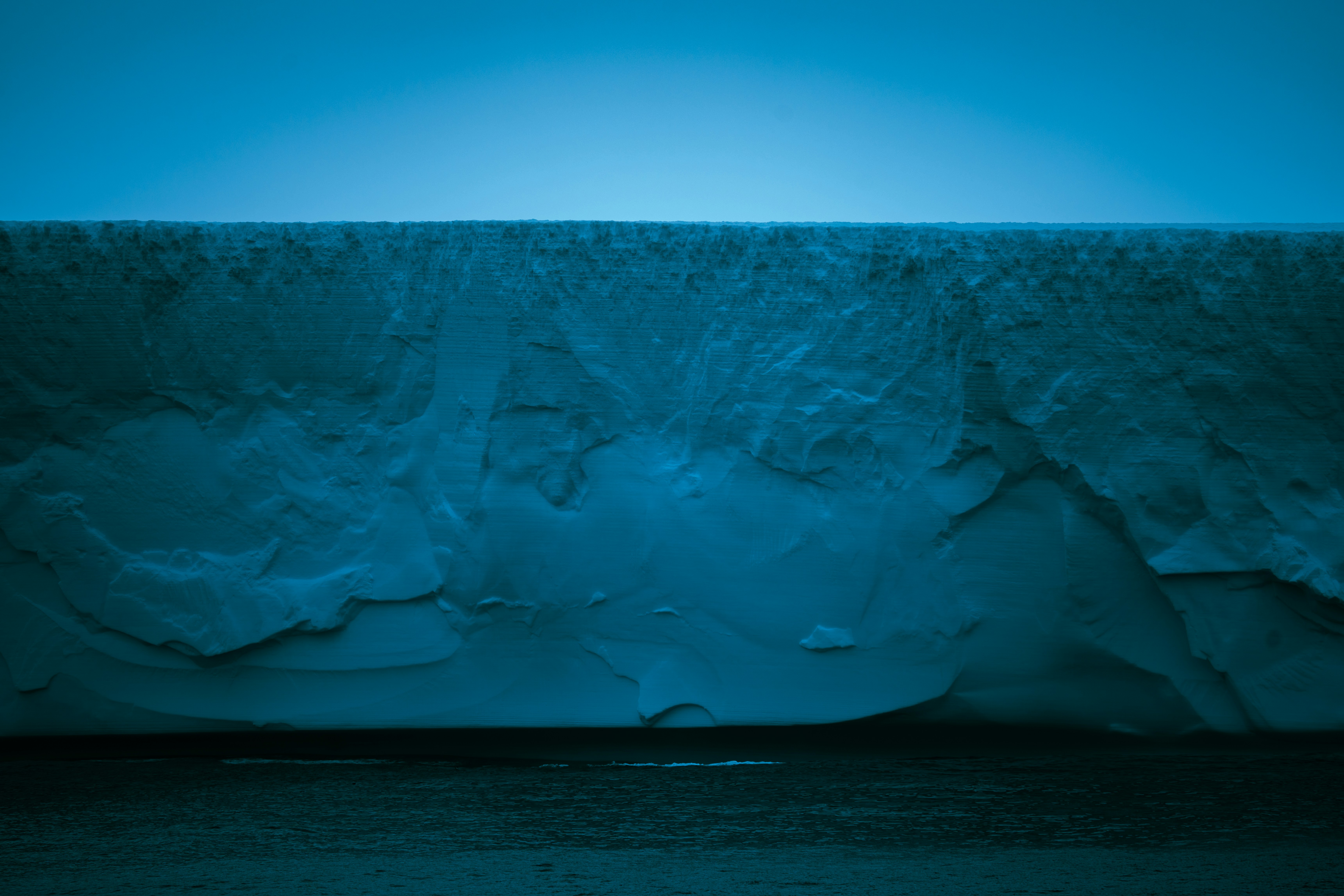 Edge of the Glacier: A Blue Ice Cliff Over the Dark Sea