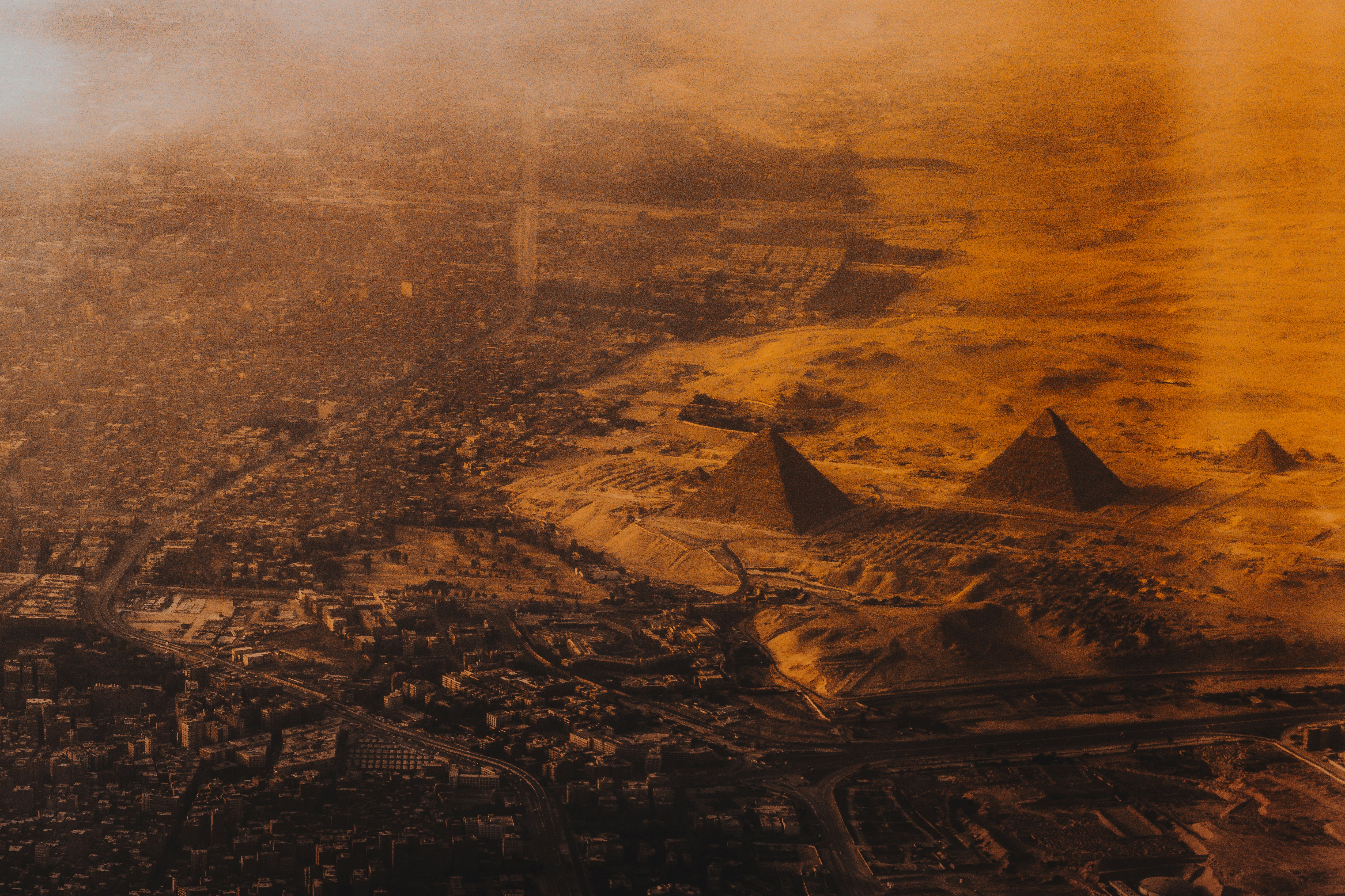 Pyramids stand in a hazy, desert landscape.