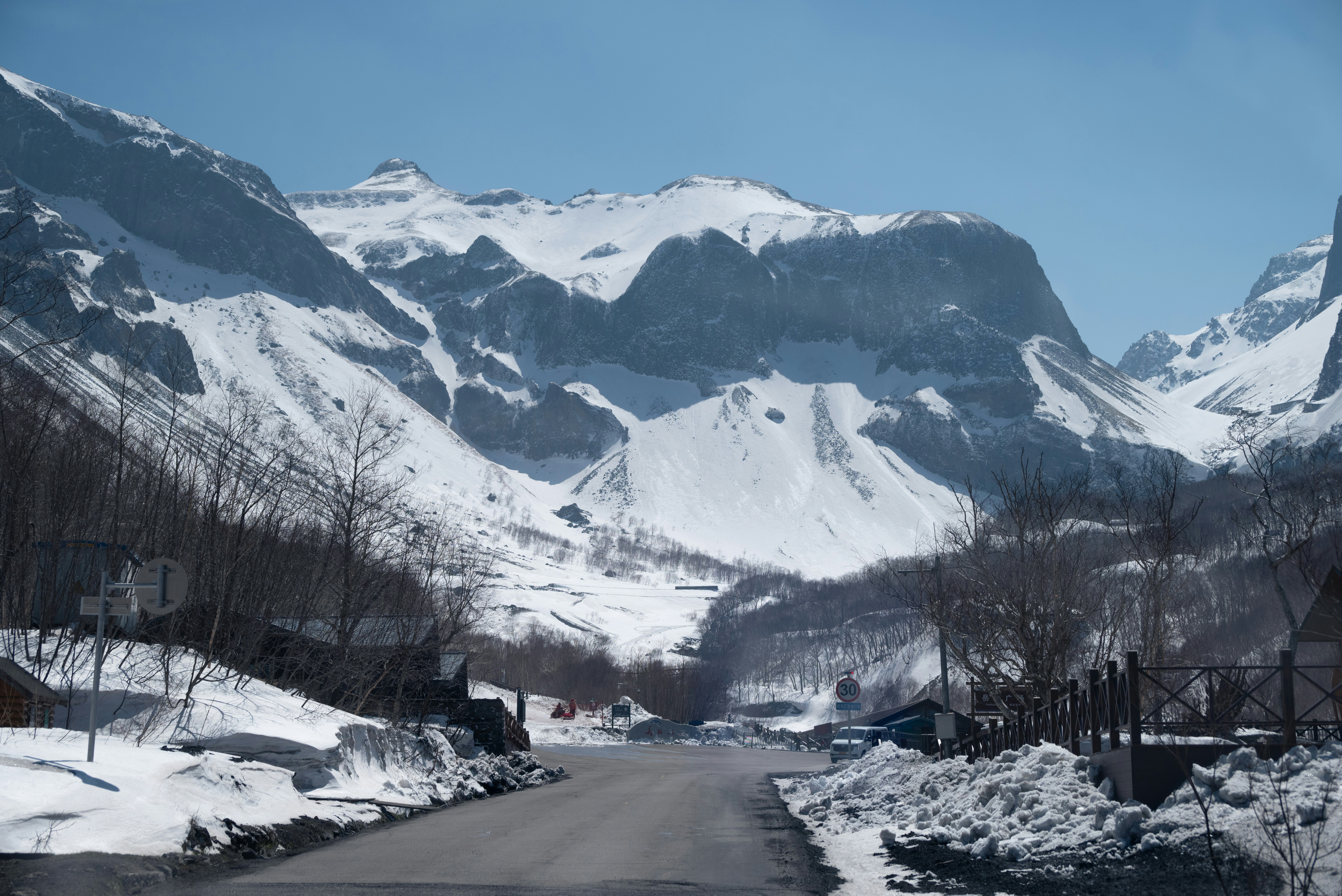 Snowbound Apex: A Mountain Hamlet Emerges Along a Quiet Snow-Cleared Road