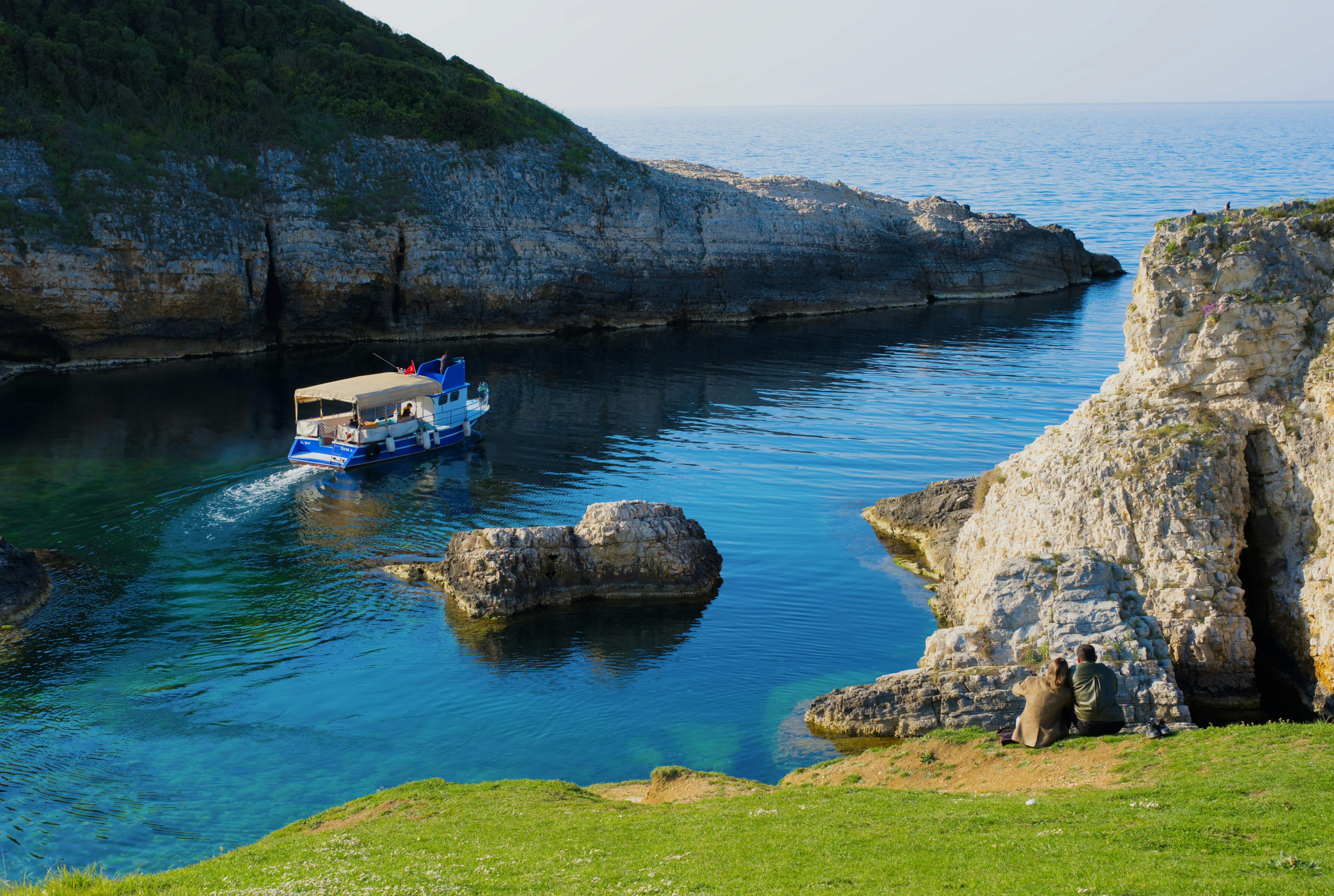 Blue Boat in a Quiet Cove: Sunlit Rocks and Clear Turquoise Water