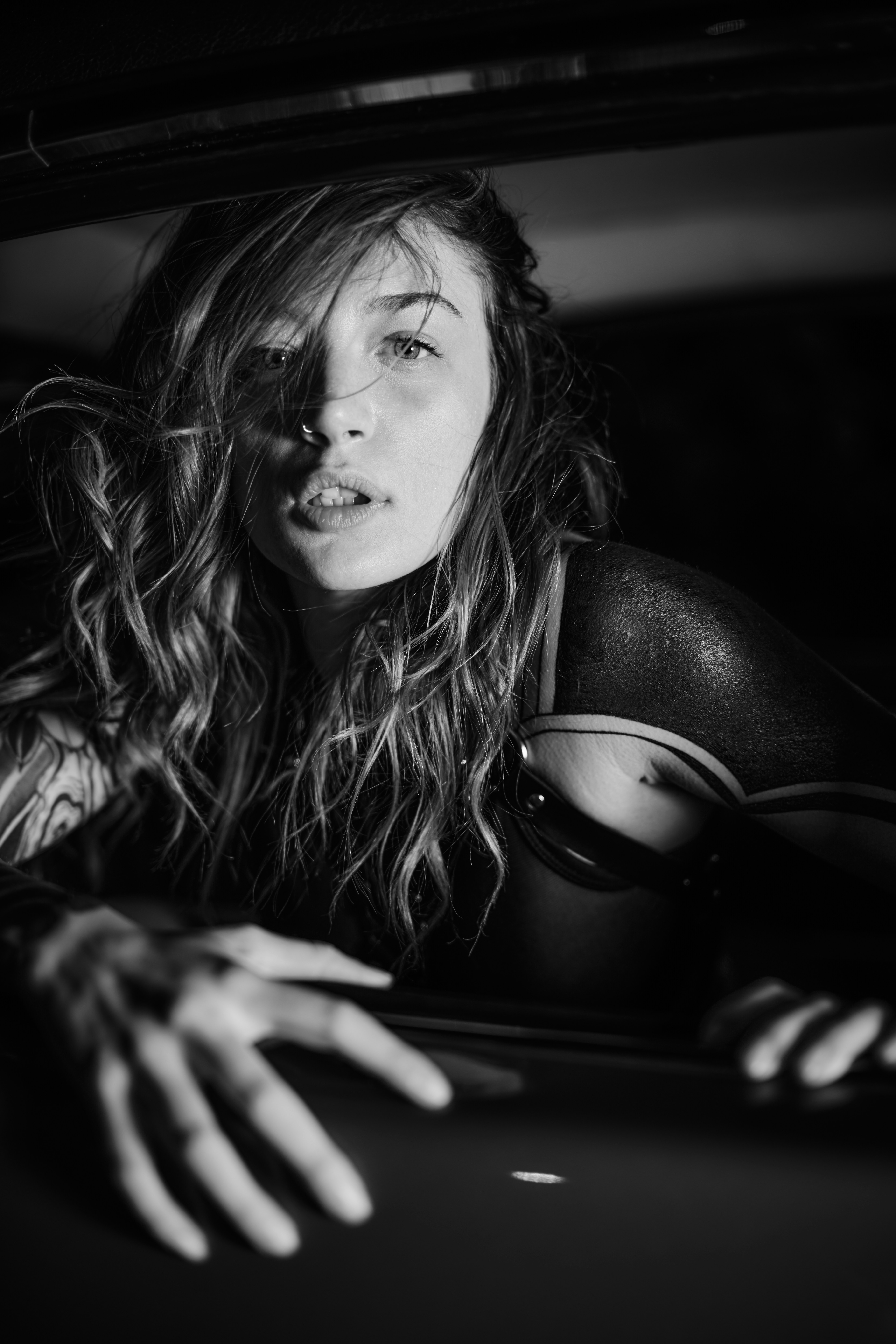 Glimmered Gaze Through Glass: A Monochrome Portrait at the Car's Edge