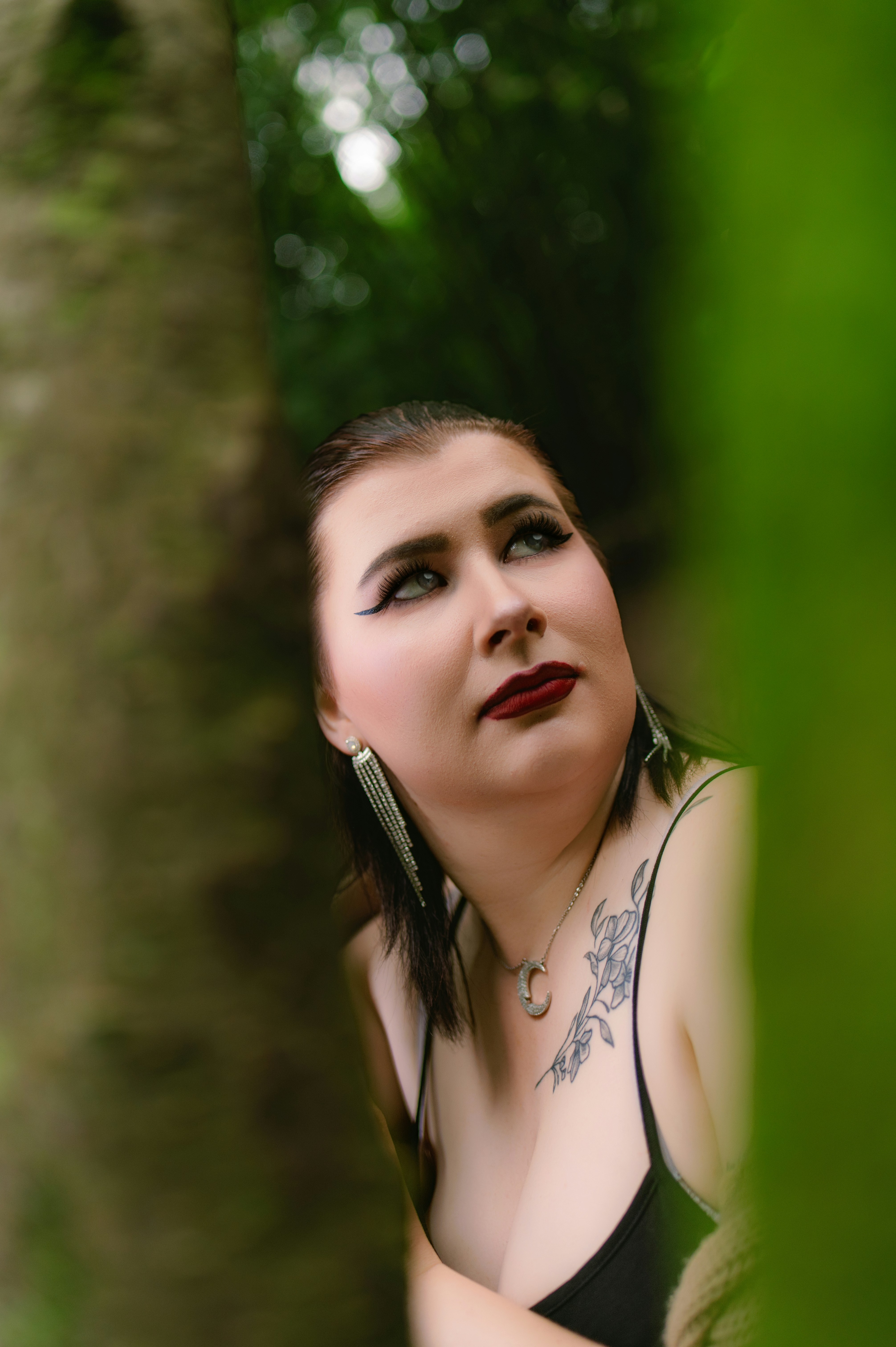 Woman in a forest looks up thoughtfully.