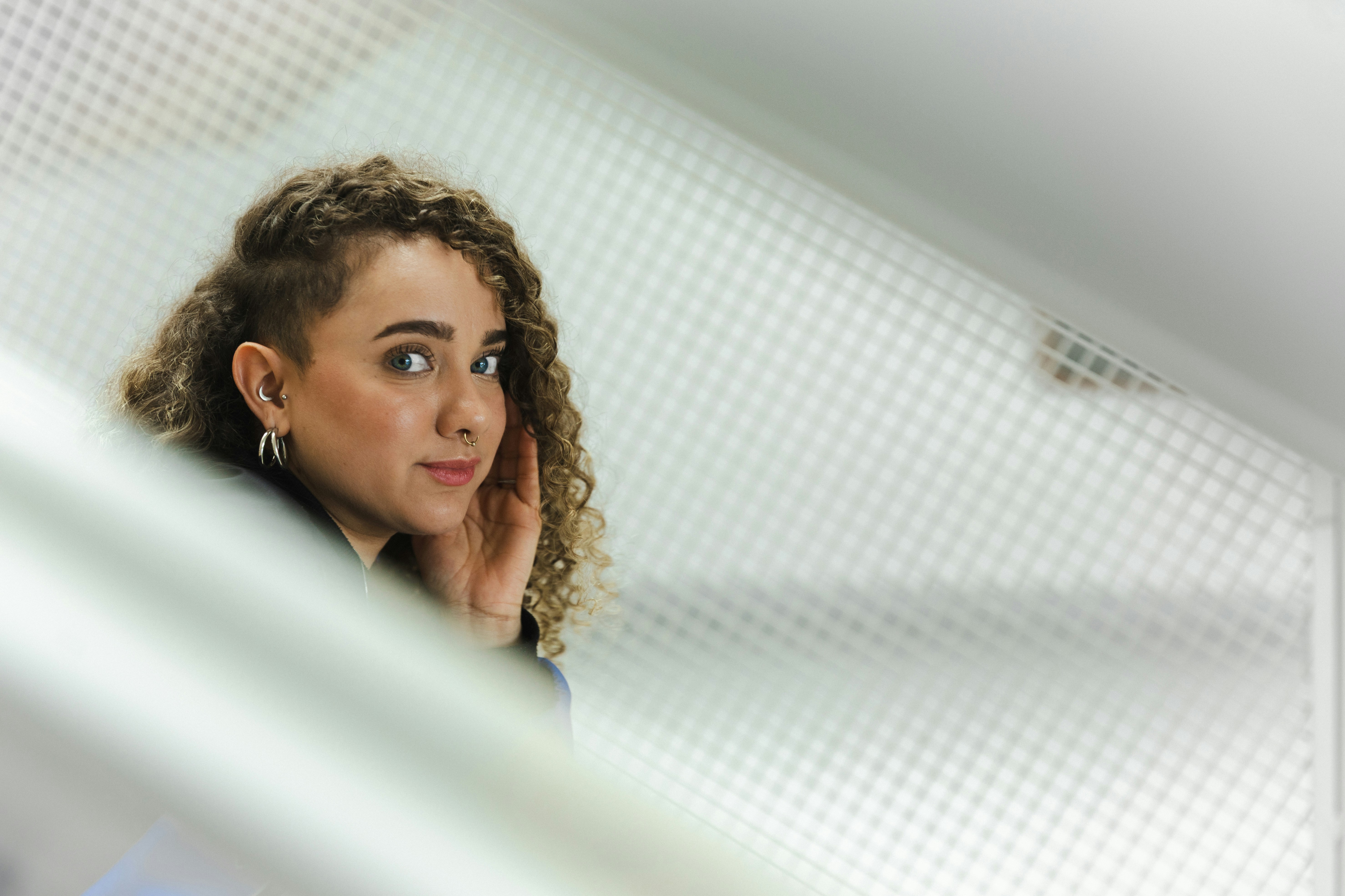 Curved light and a confident gaze: portrait through architectural mesh