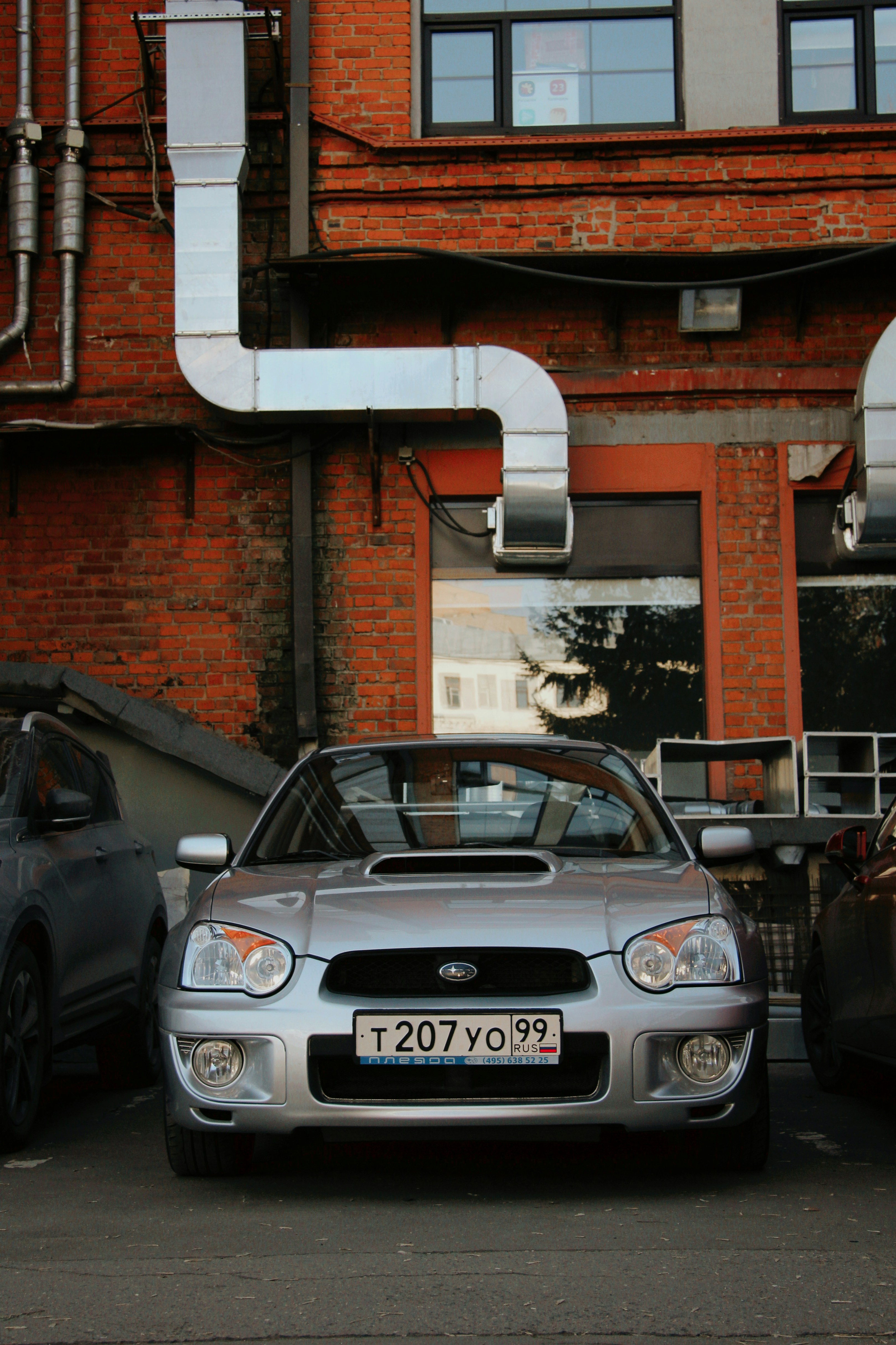 A silver subaru car is parked near a brick building. photo – Free Image ...