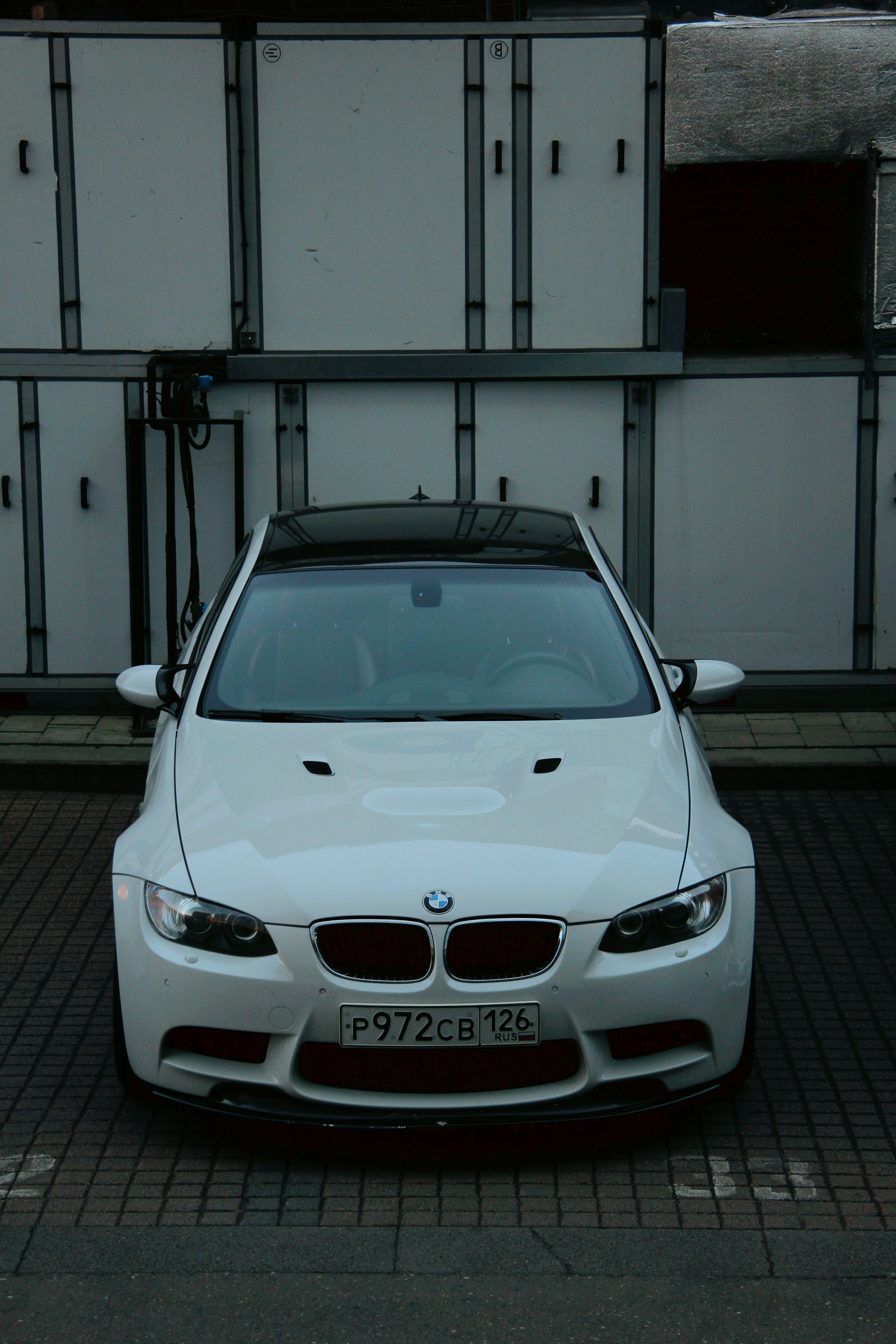 El coche BMW blanco está aparcado delante de los paneles blancos. foto ...