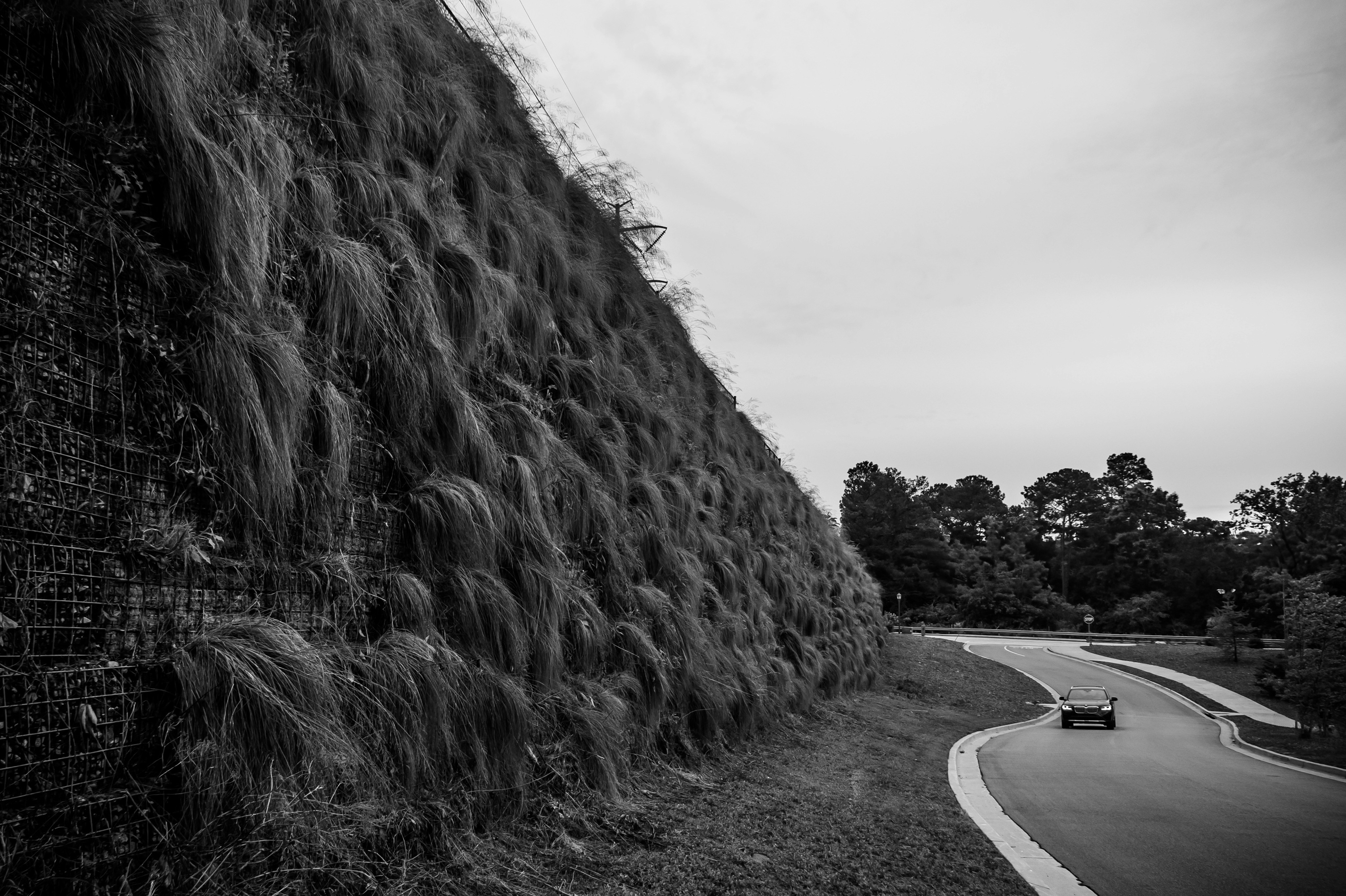 A curvy road with a car beside a wall.