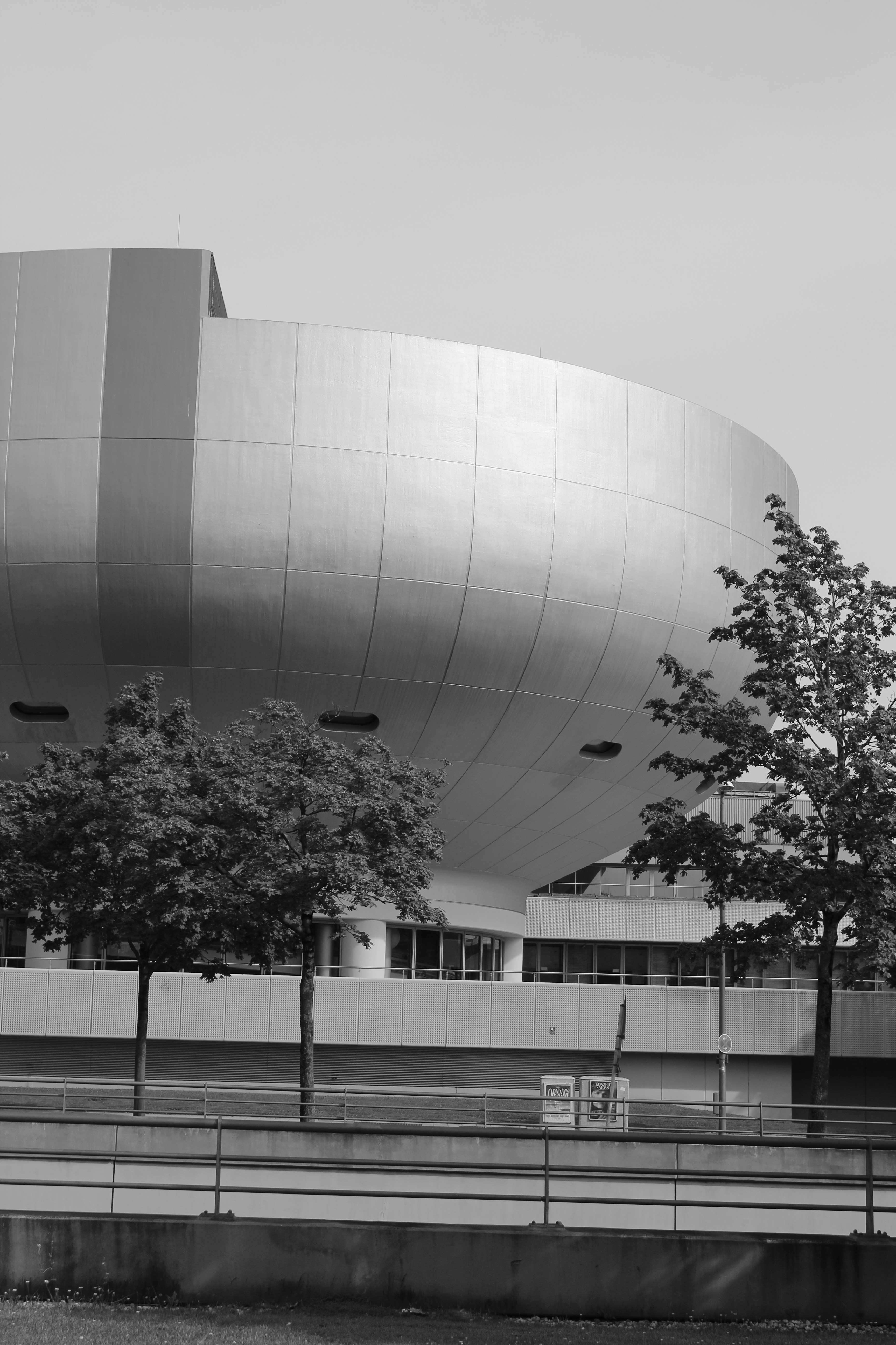 Echoes of Steel: A Curved Pavilion Looms Over a Quiet Street