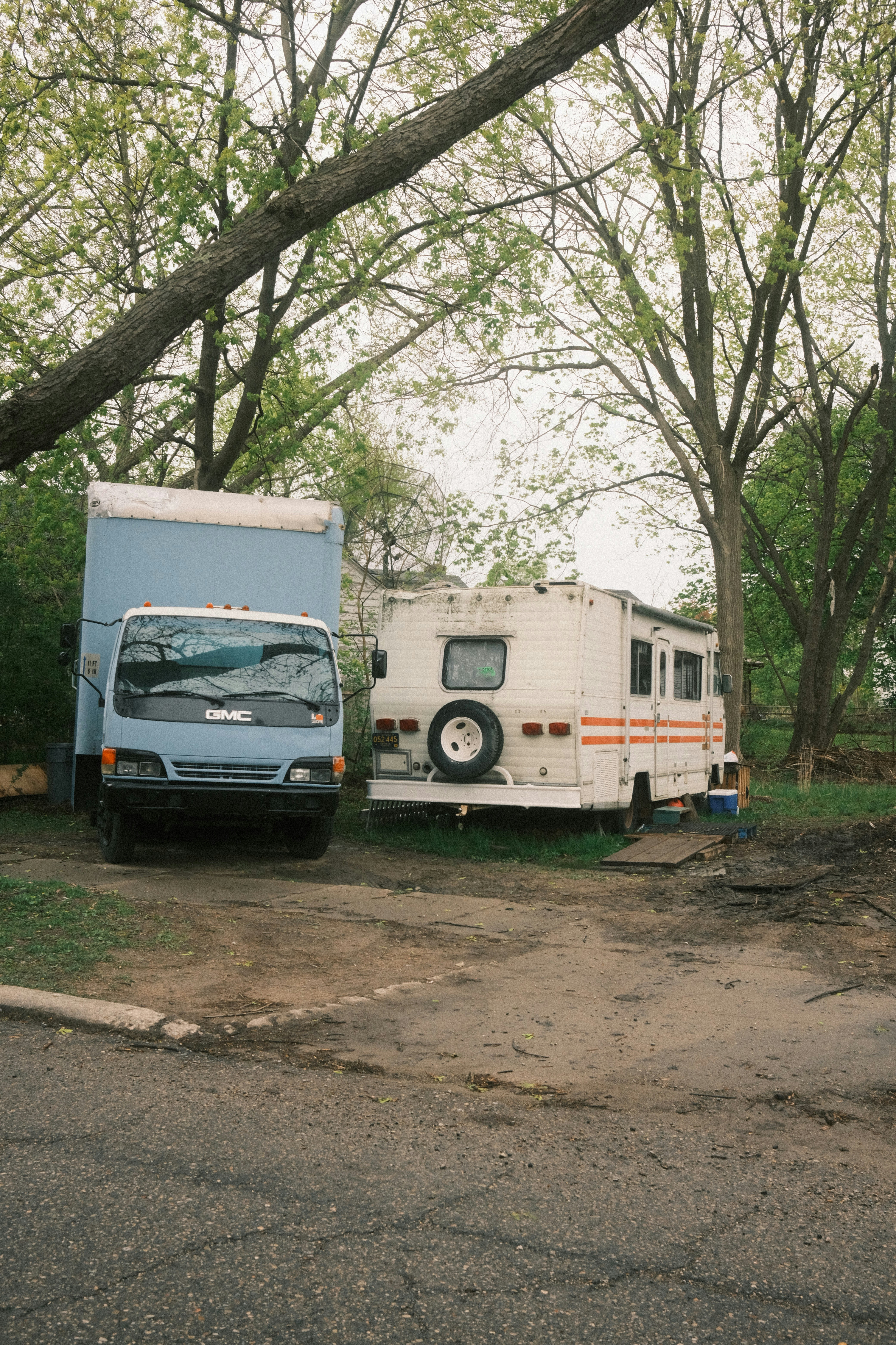 Grove-side Parking: A Blue GMC and a Vintage Camper in Spring Light