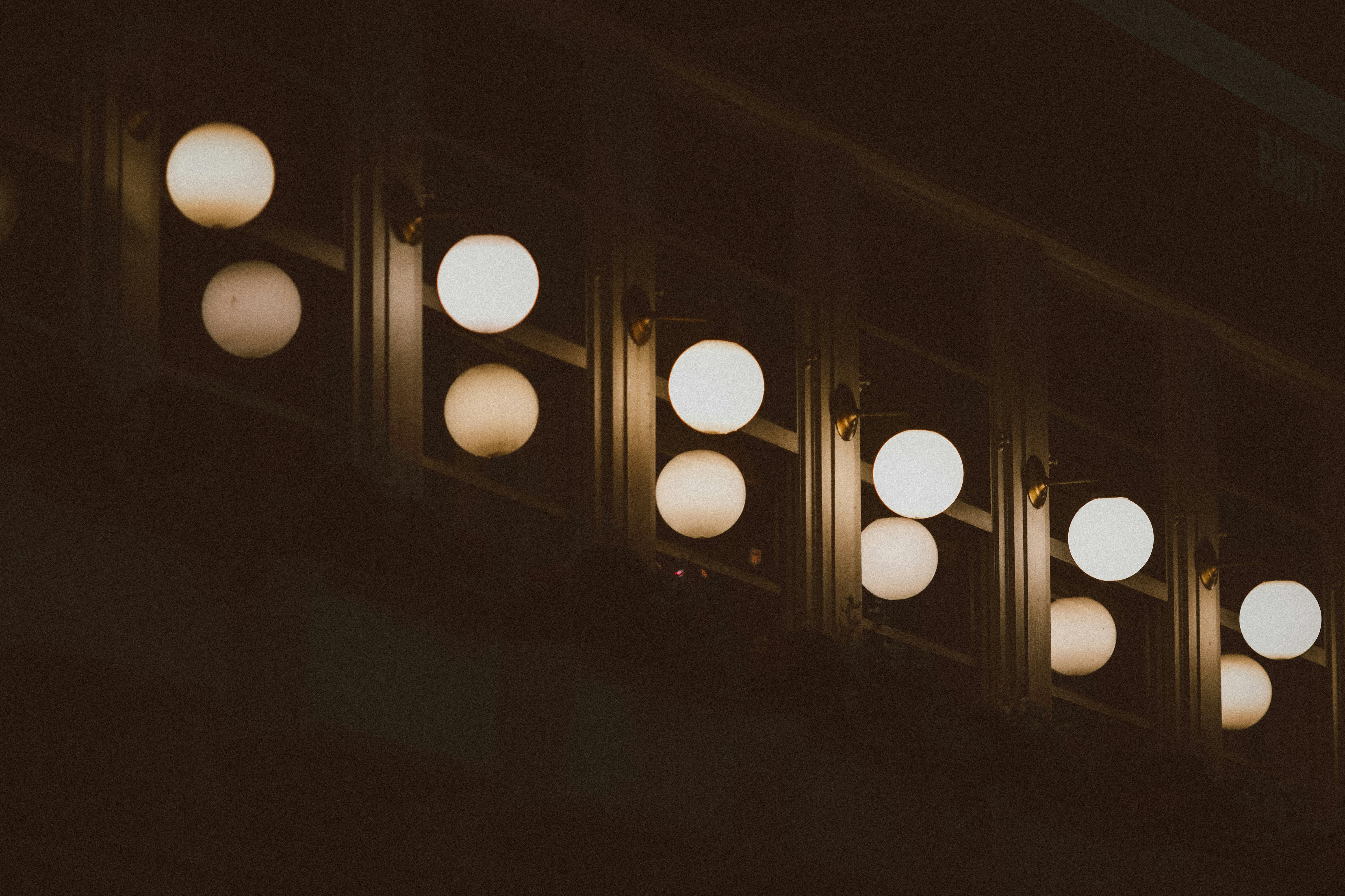 Series of round lights glowing against a dark backdrop, creating a warm ambiance in an urban setting.