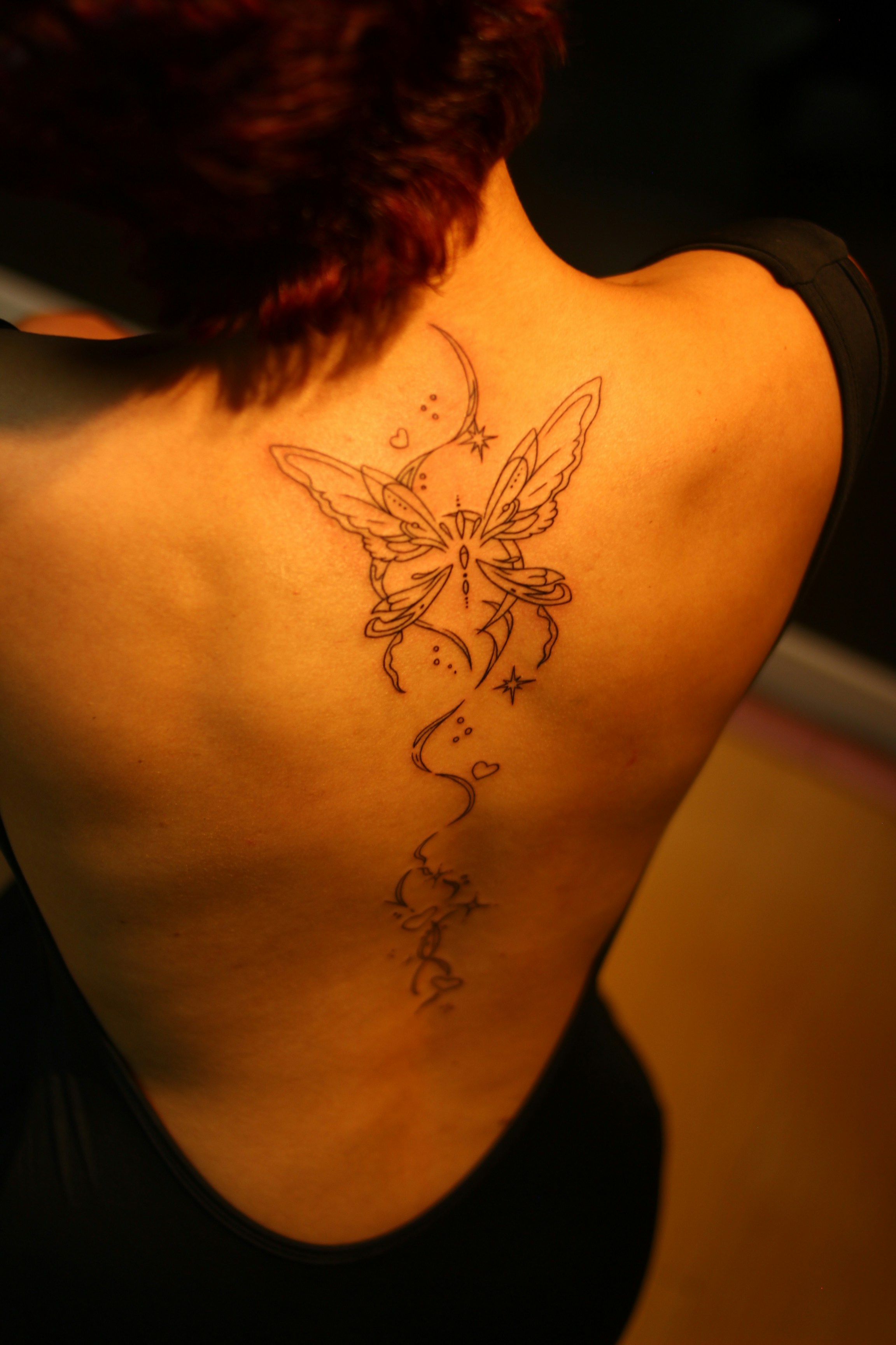 Butterfly Along the Spine: Amber Light Illuminates a Tattooed Wing