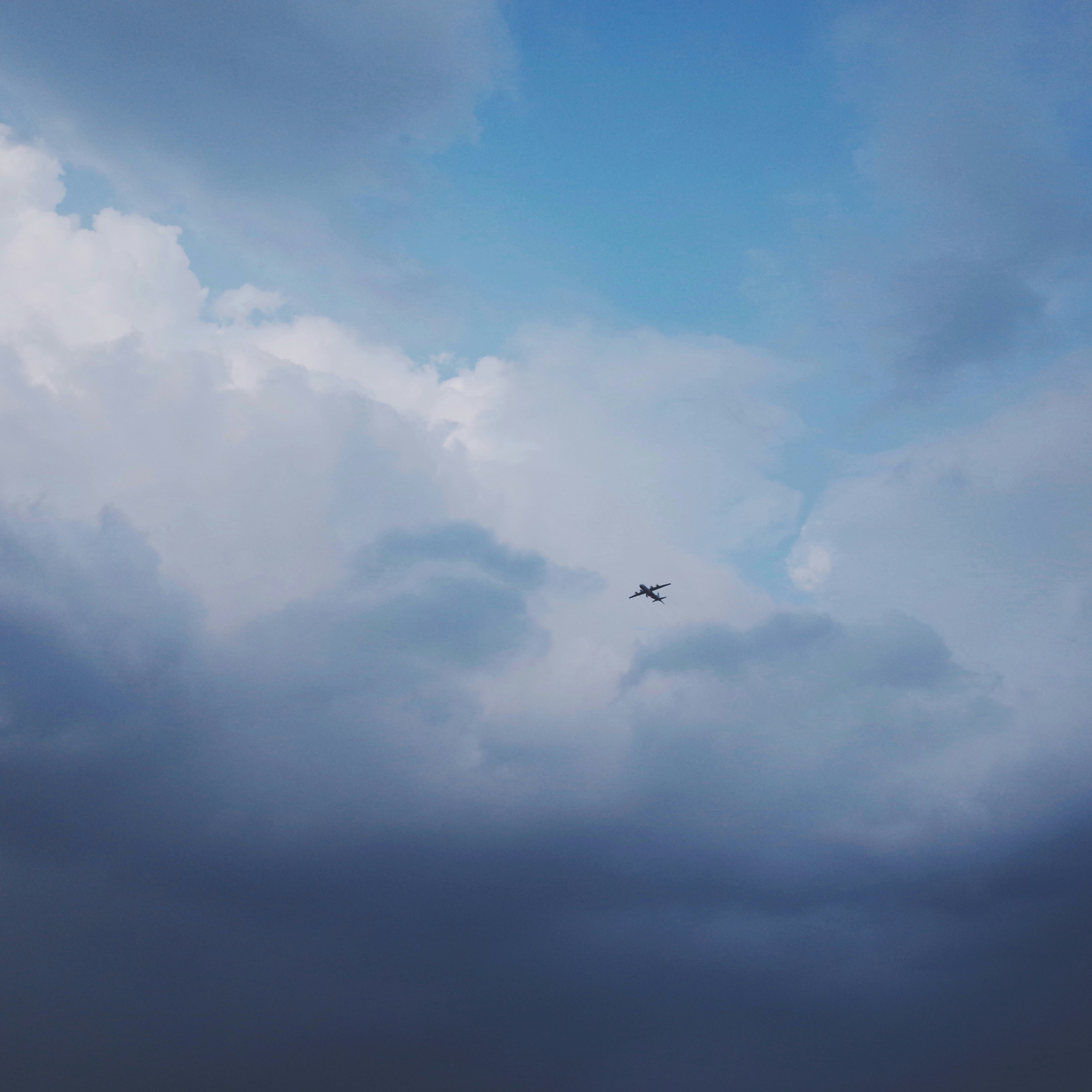 An airplane glides gracefully through a canvas of blue sky and fluffy clouds, evoking a sense of adventure and exploration.