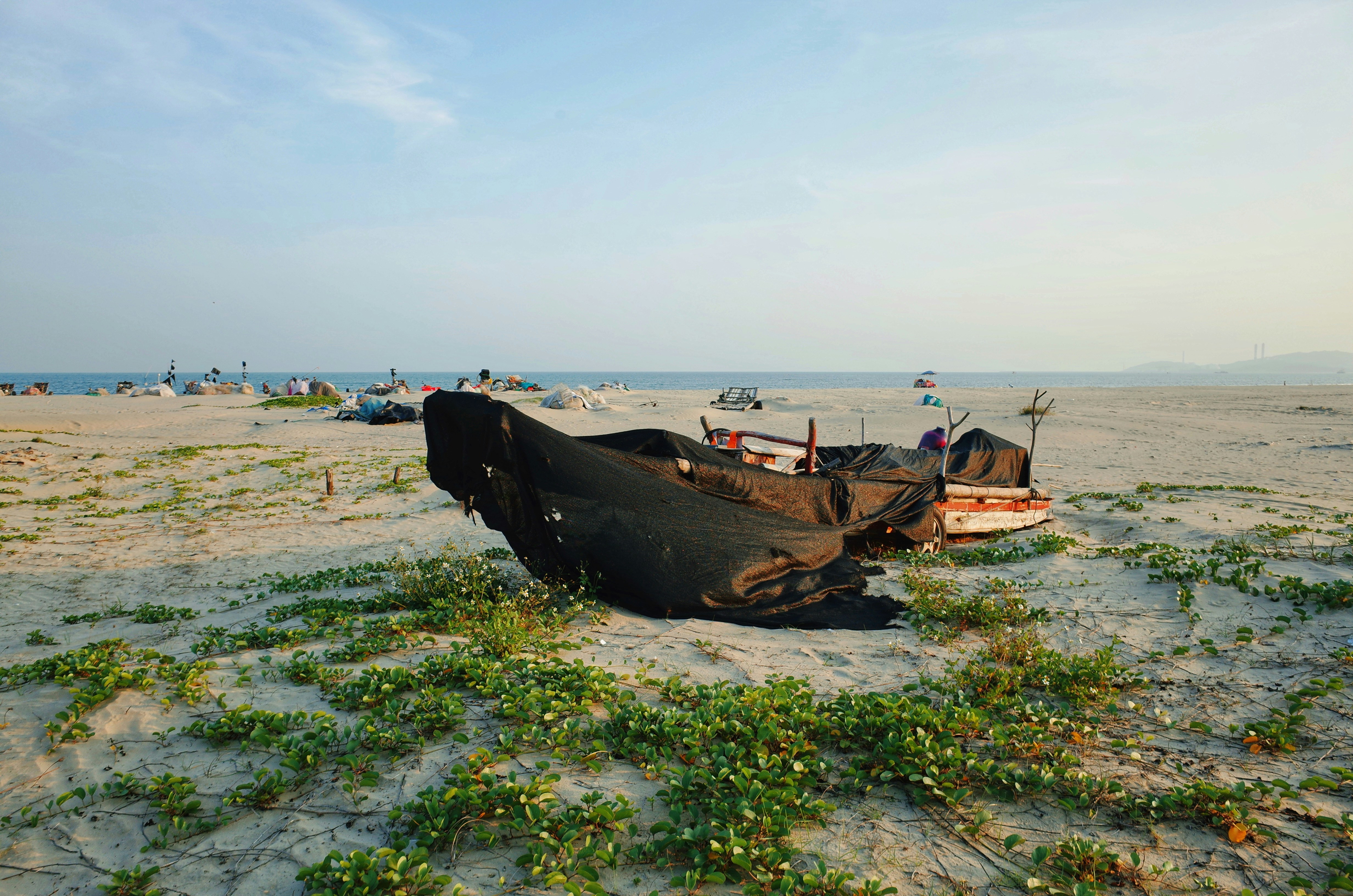Tattered Boat Resting on a Sparse Beach Under a Wide Sea Sky