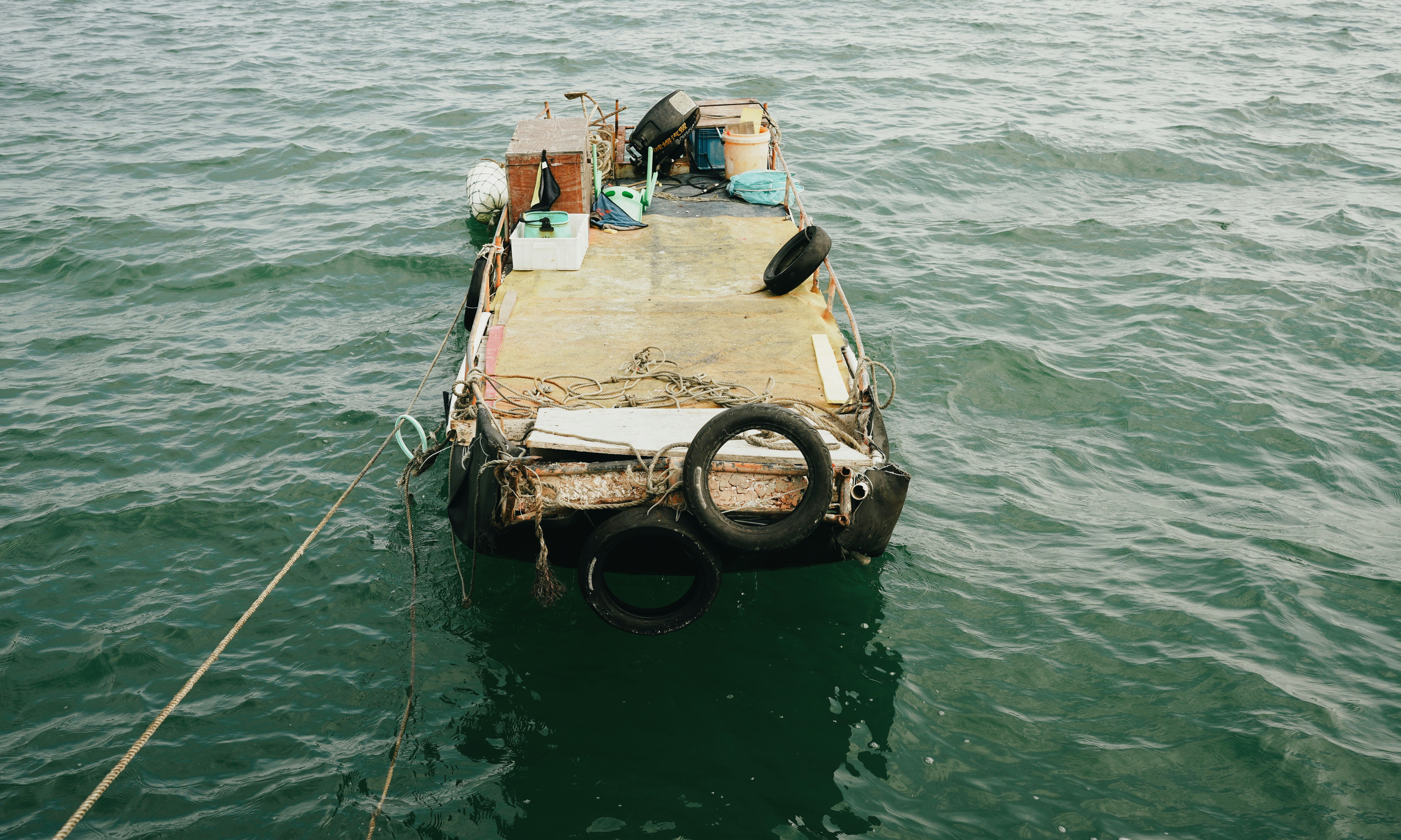Emerald Drift: Weathered Workboat Tethered by Tires on Jade Waters