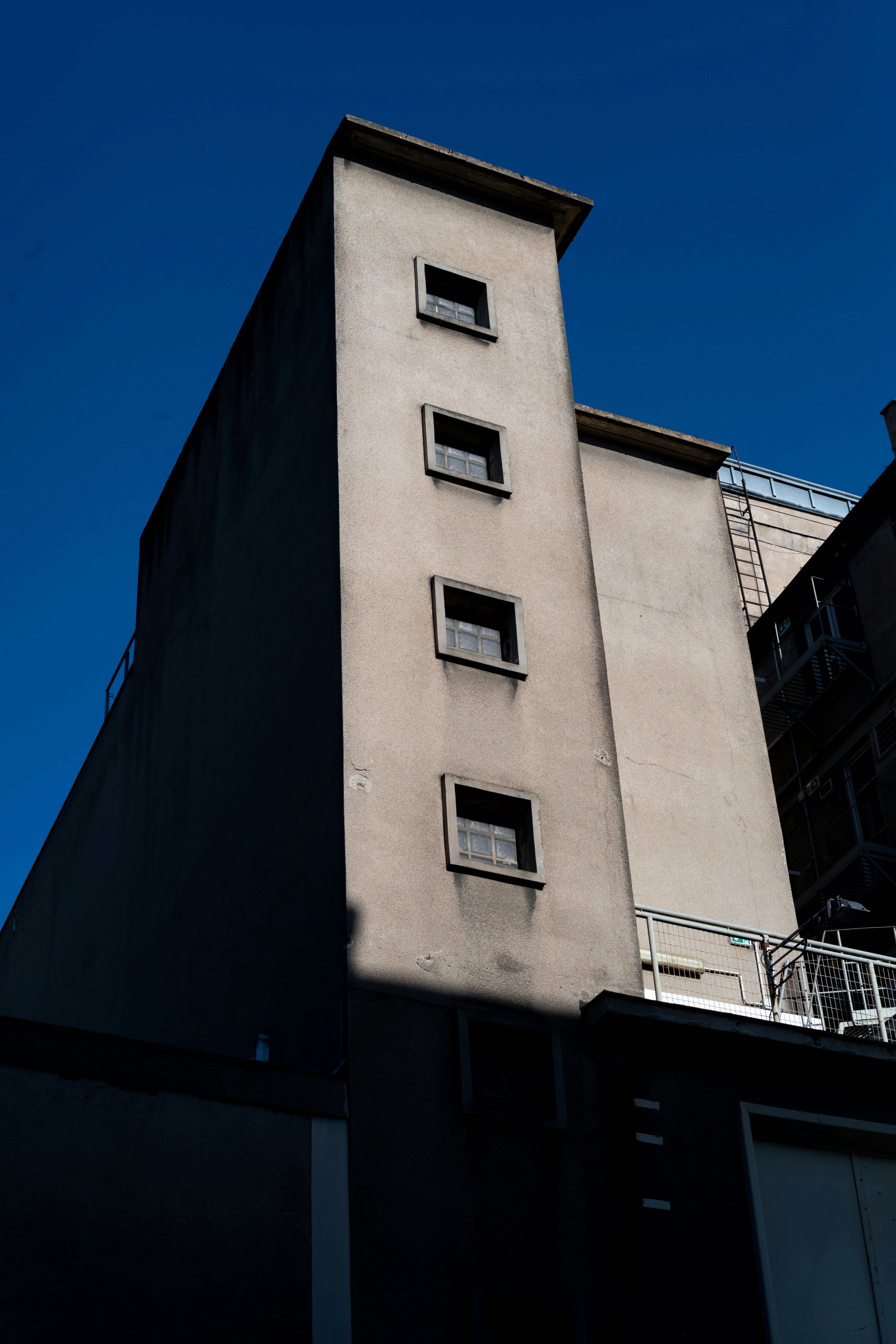A tall concrete building rises against a blue sky.