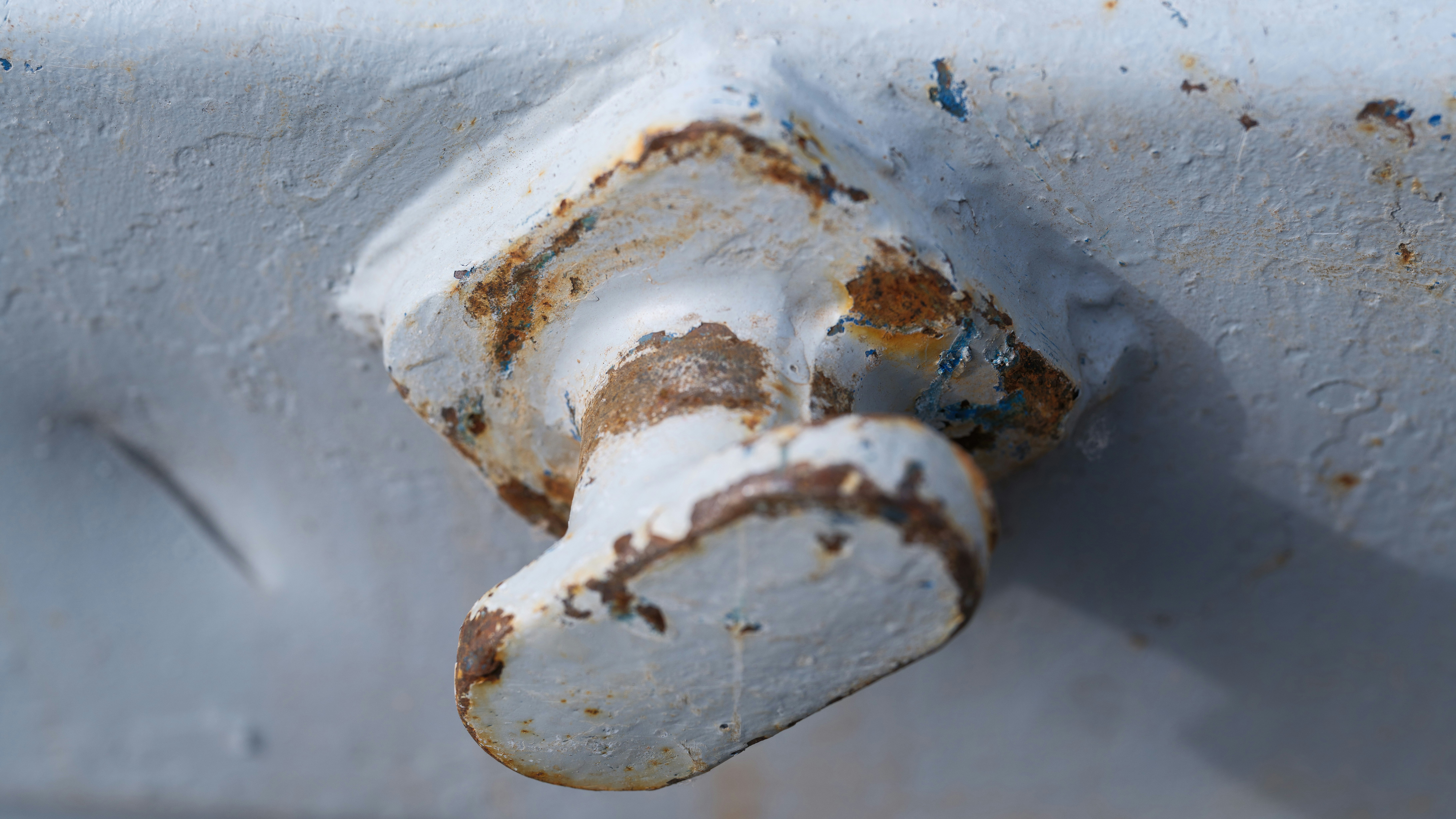 Patina Portrait: Close-Up of a Rusted White Bolt Anchored in Weathered Blue Steel