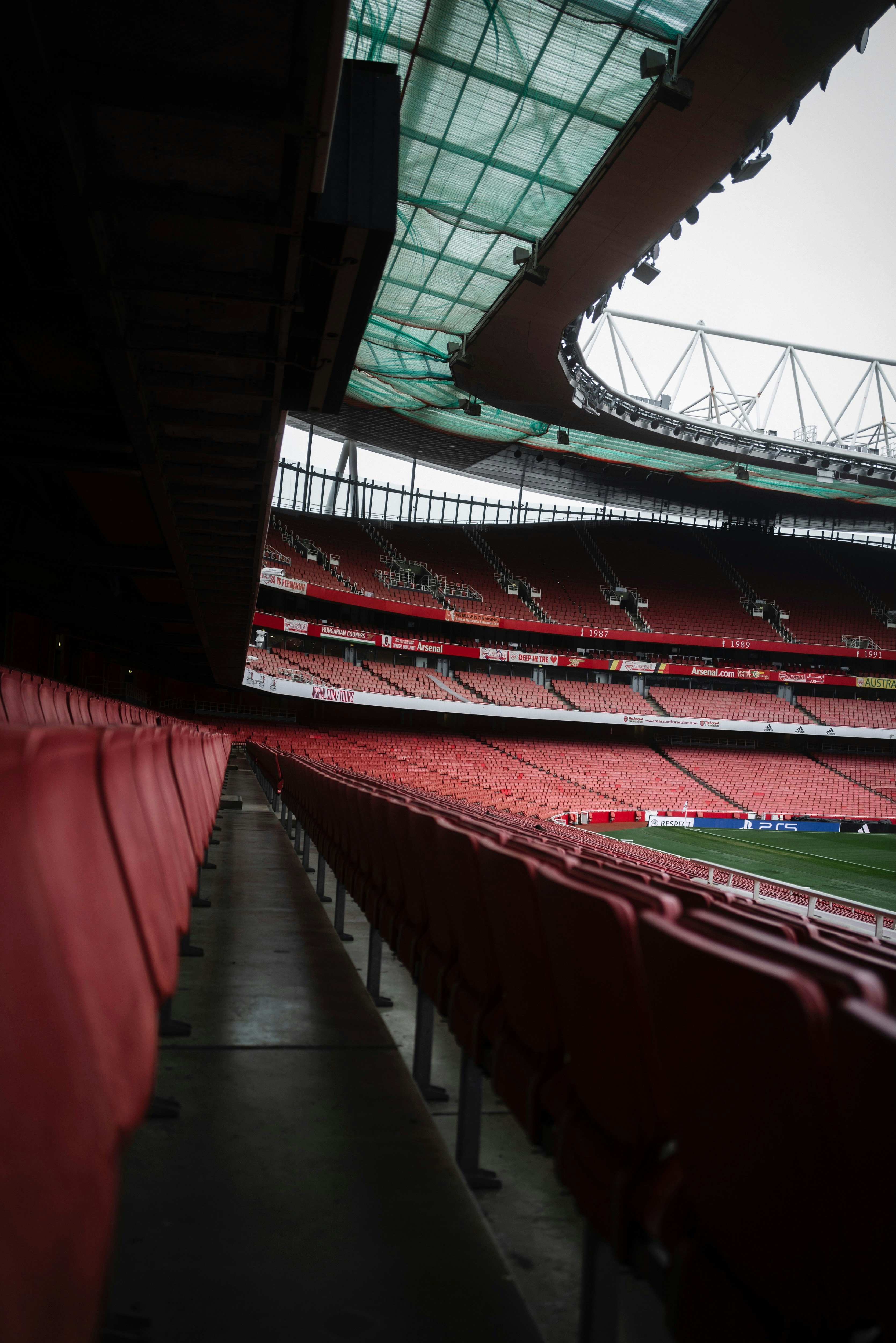 Stadium Aisle: Red Seats Recede into Shadowed Tunnel
