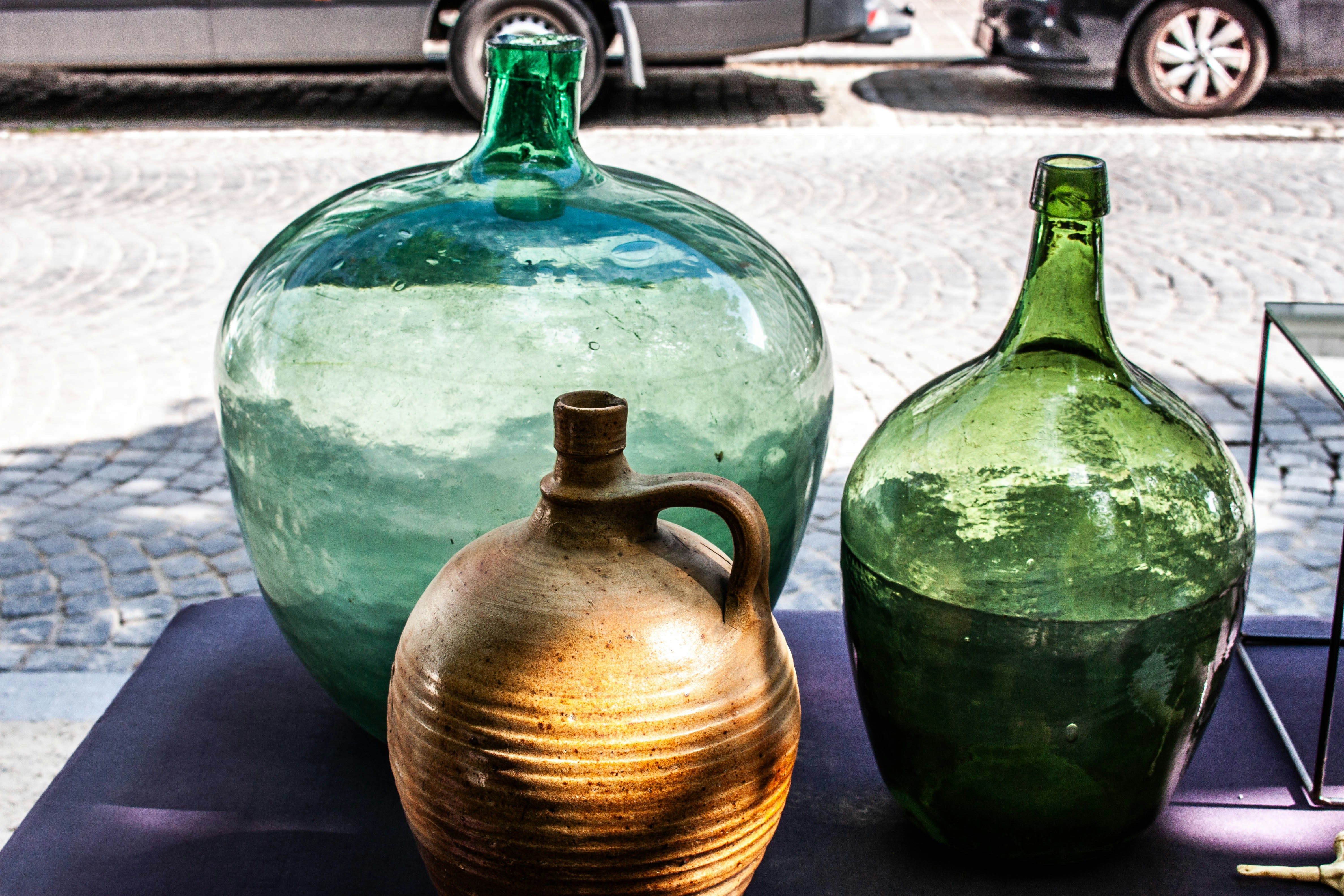 Amber Jug Anchored Between Verdant Bottles on a Cobblestone Table