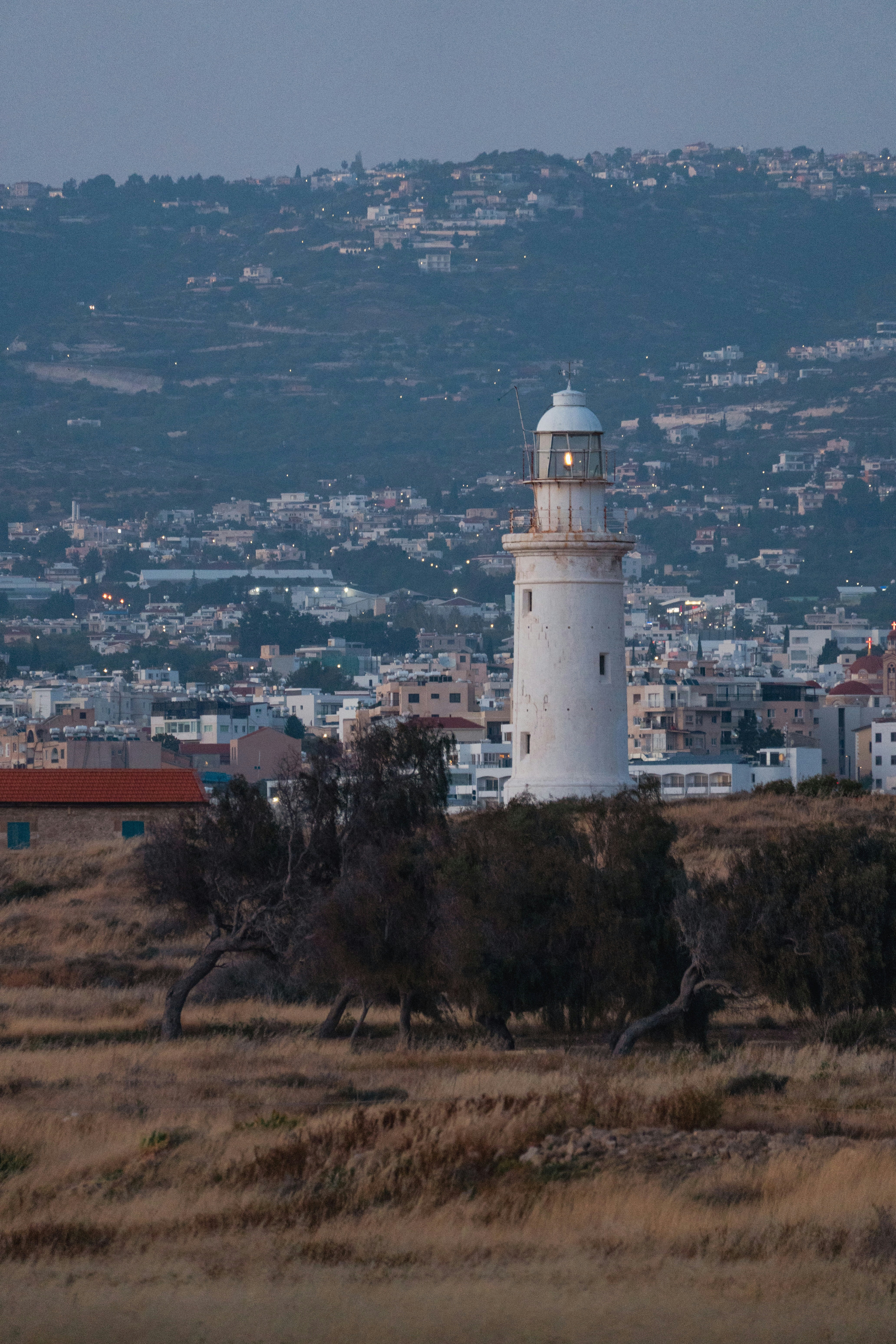 Lighthouse overlooking a coastal town surrounded by mountains.