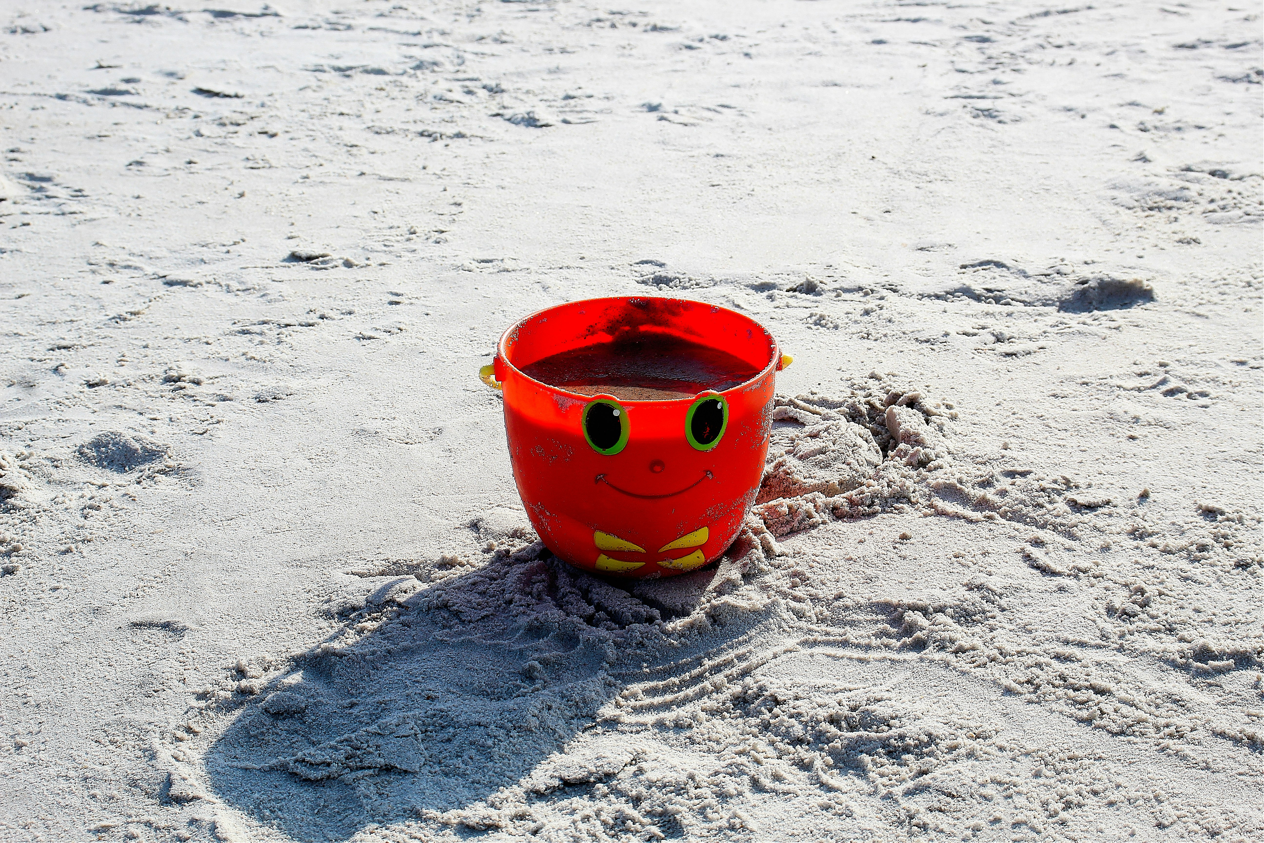 A red bucket sits on the sandy beach. photo – Free Sand Image on Unsplash