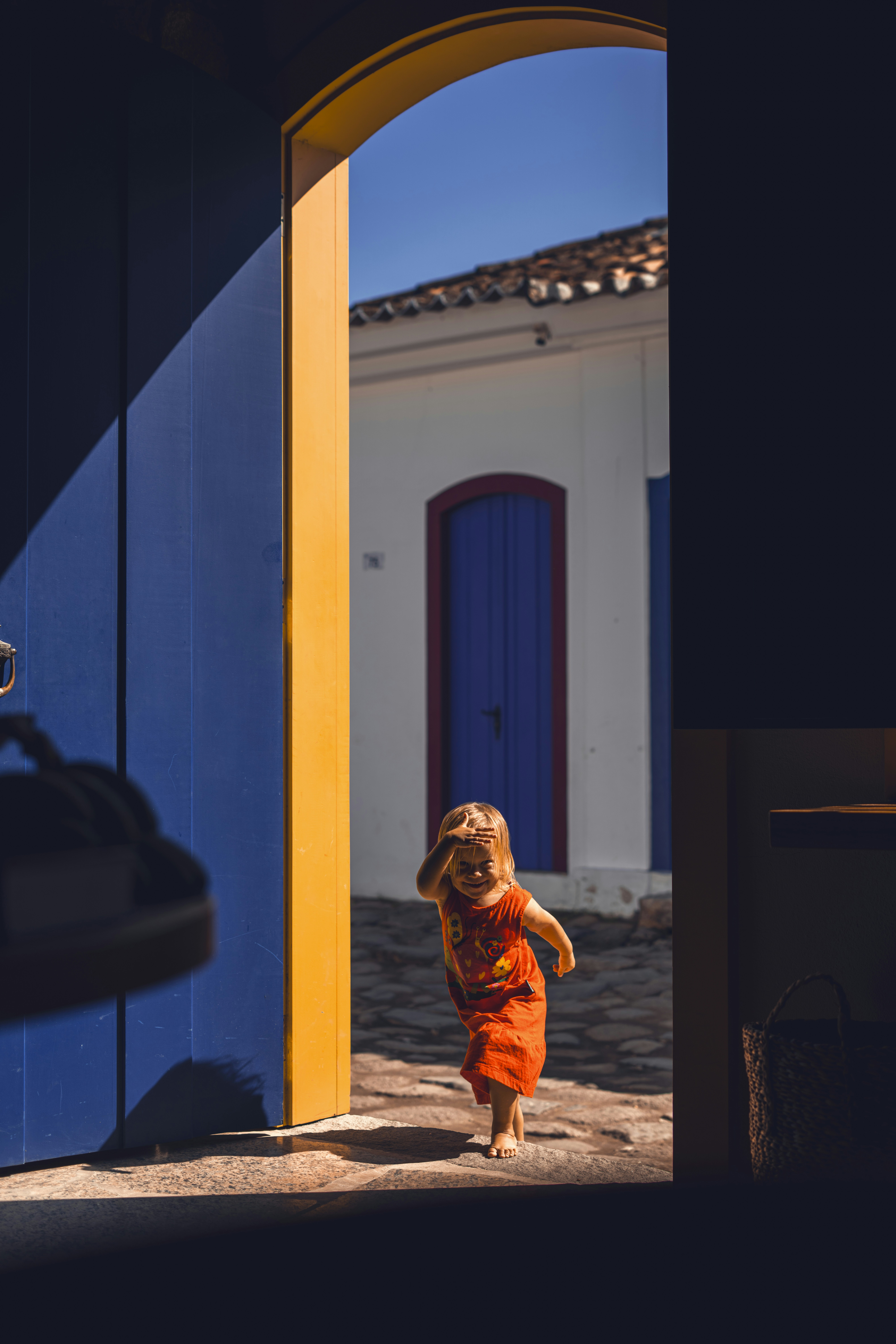 Sunlit Threshold: A Child in an Amber Doorway Framed by Blue Walls