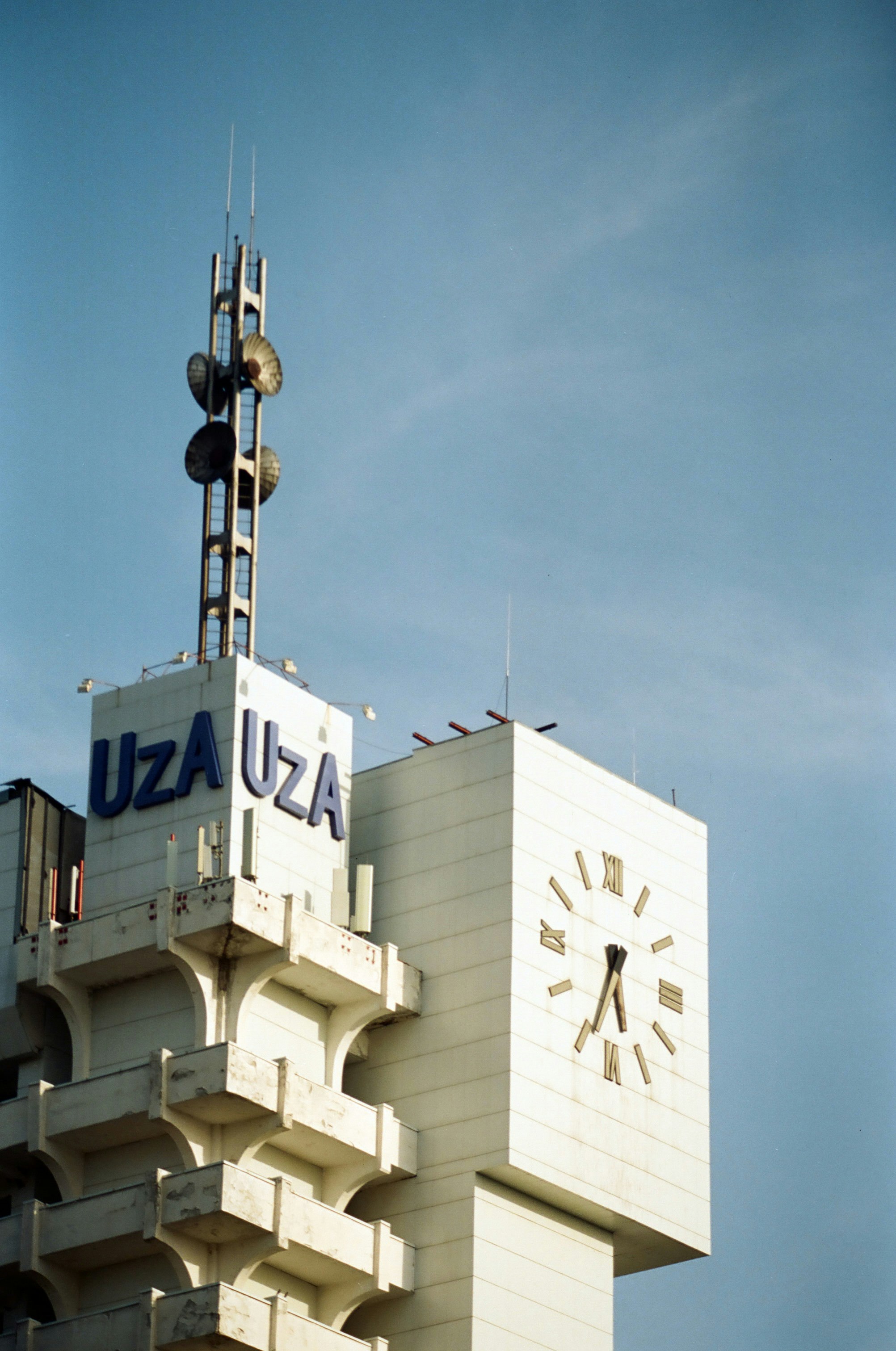 A white building features a clock and antennas. photo – Free Film ...