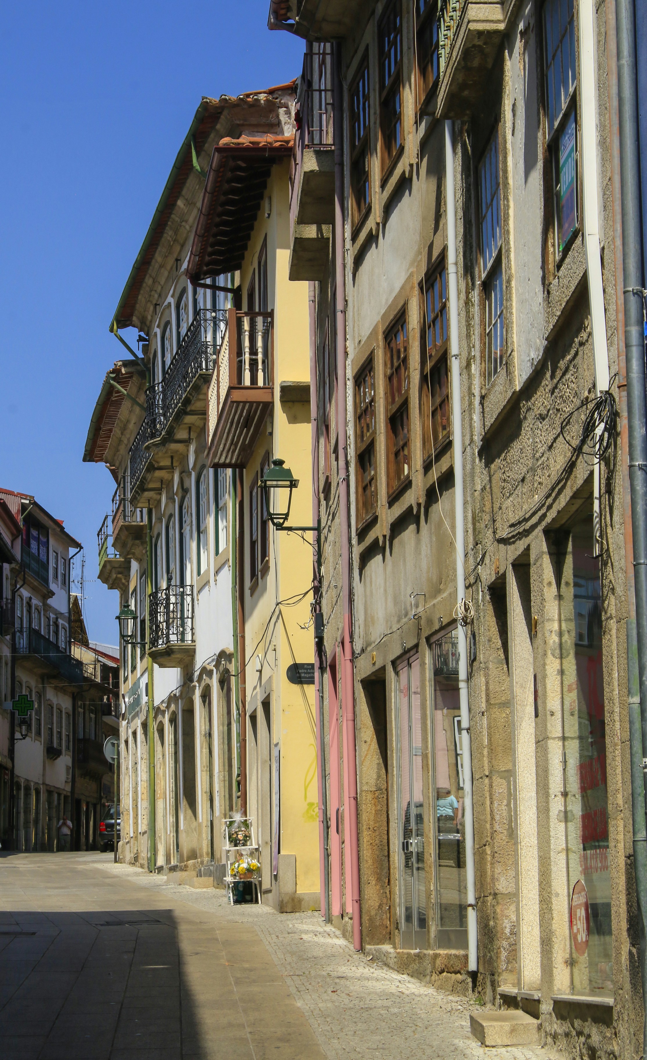 Charming street lined with historical buildings showcasing unique architectural details and vibrant colors. Soft sunlight casts gentle shadows on the cobblestones.