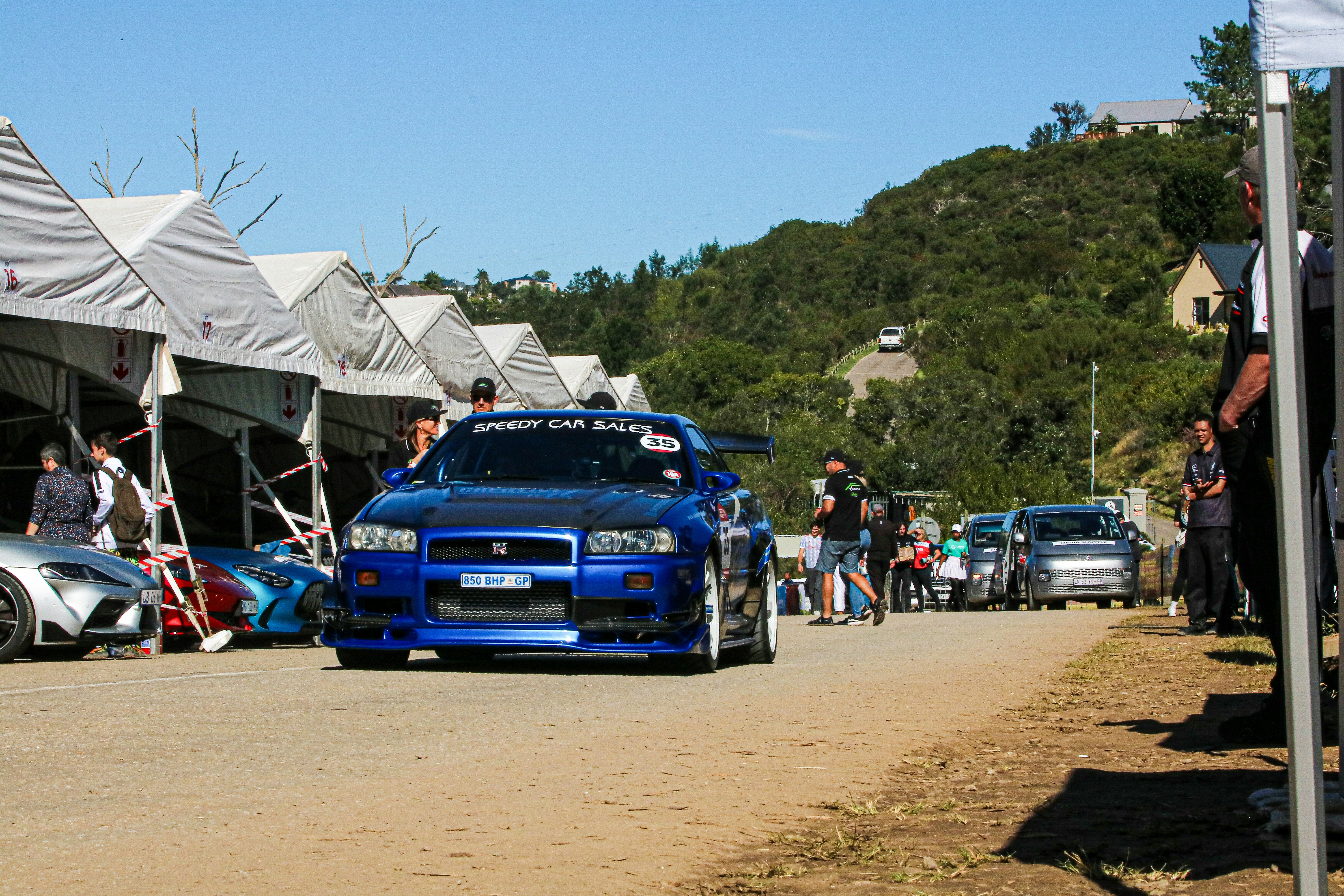 A blue car drives through a car show. photo – Free Image on Unsplash