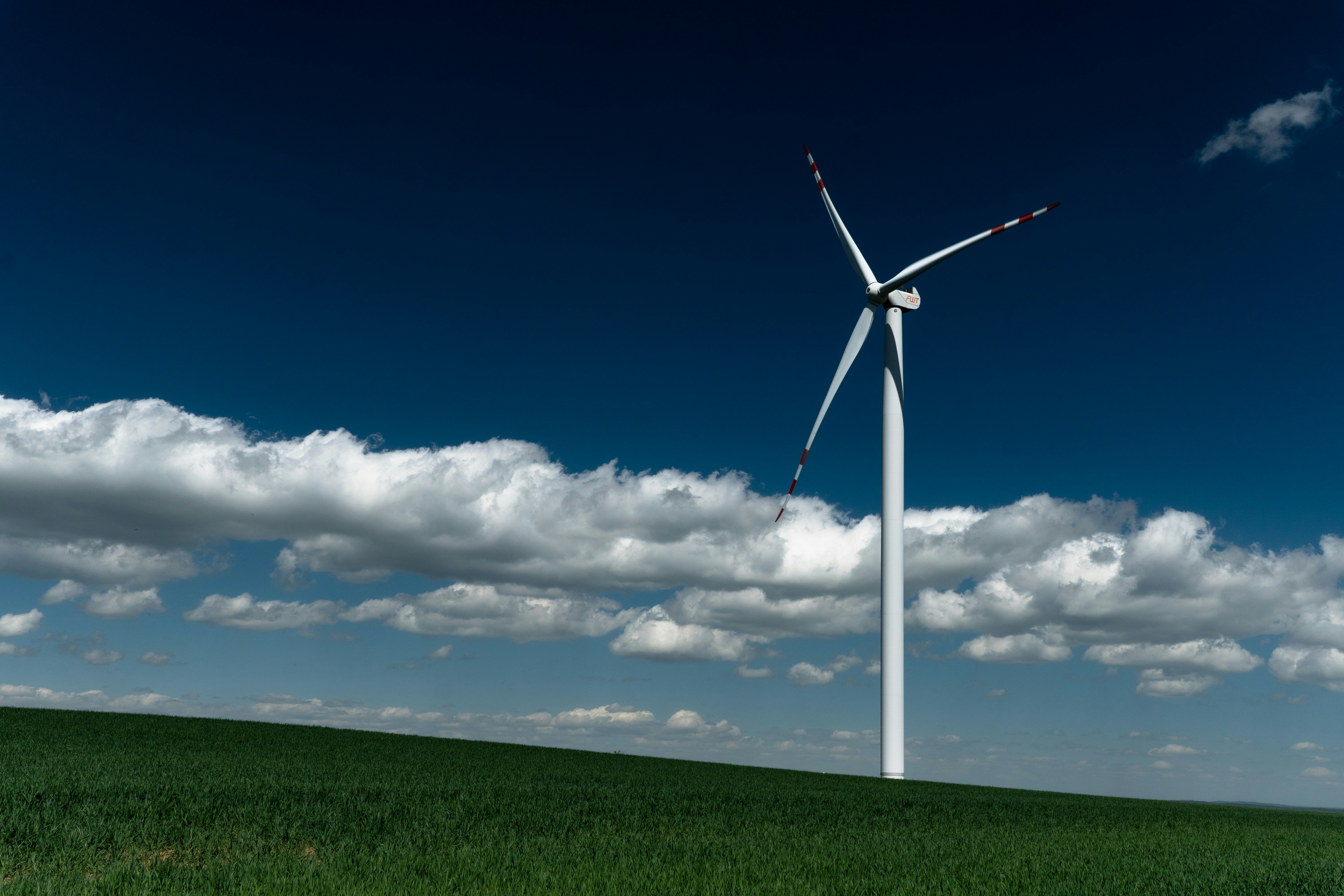 A wind turbine stands tall against a blue sky. photo – Free Spring ...
