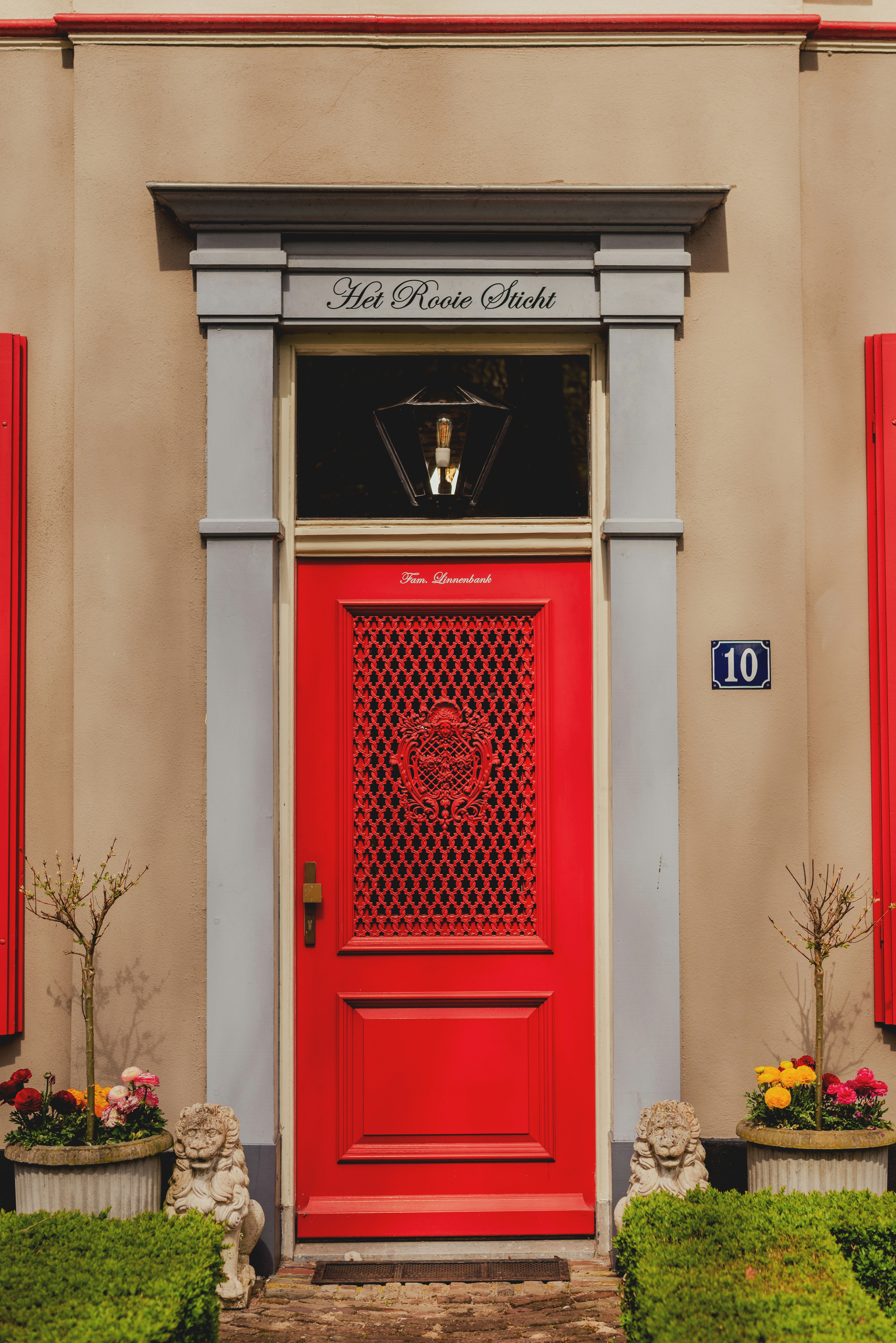 Crimson Doorway: A Bold Red Entrance Framed by Soft Stucco and Plantings