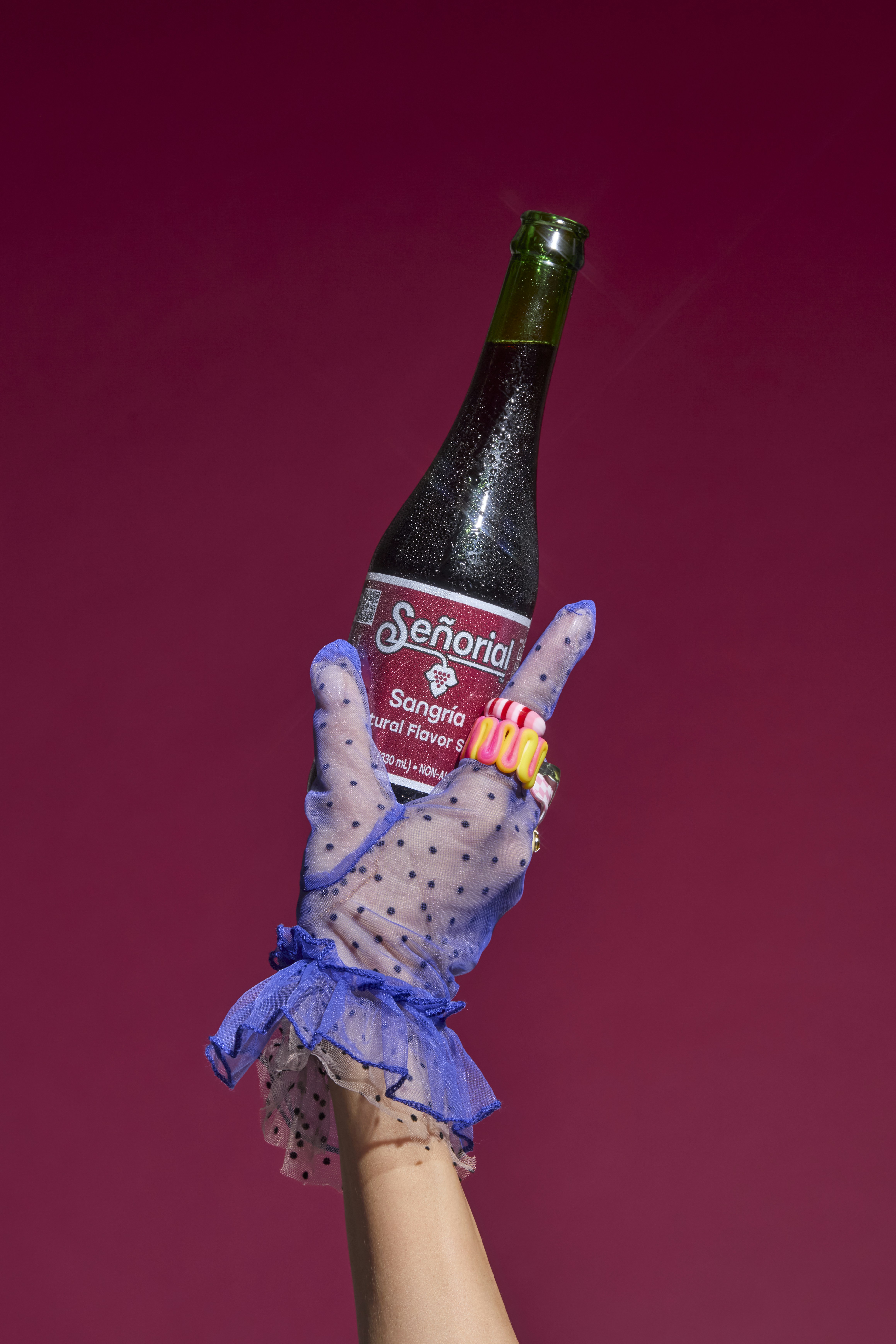 Polka-Dot Glove Elevates a Señoría Sangria Bottle Against a Magenta Backdrop