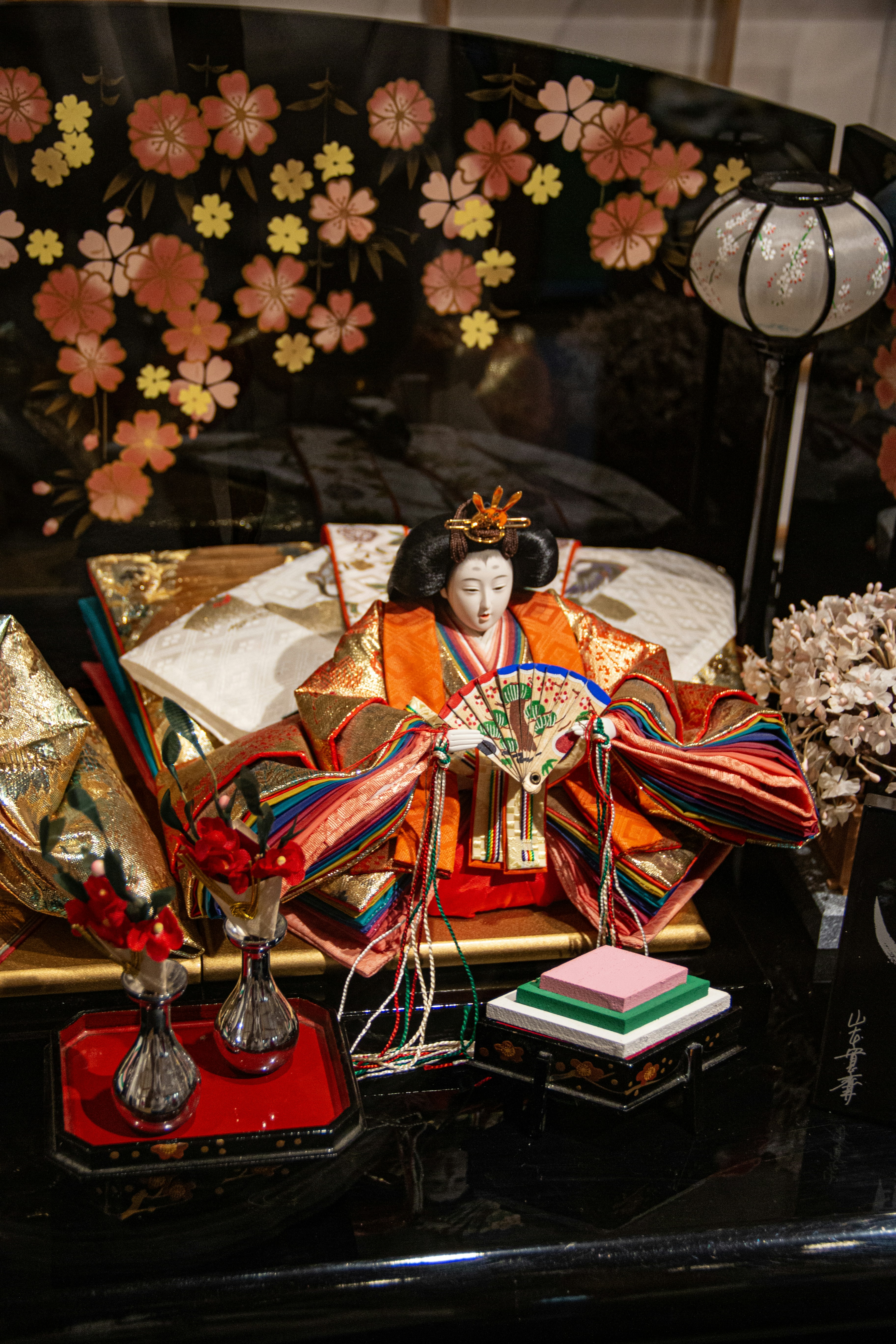 Embroidered Reverie: A Hina Ningyo Adorned with Vivid Fabrics and Lantern Light